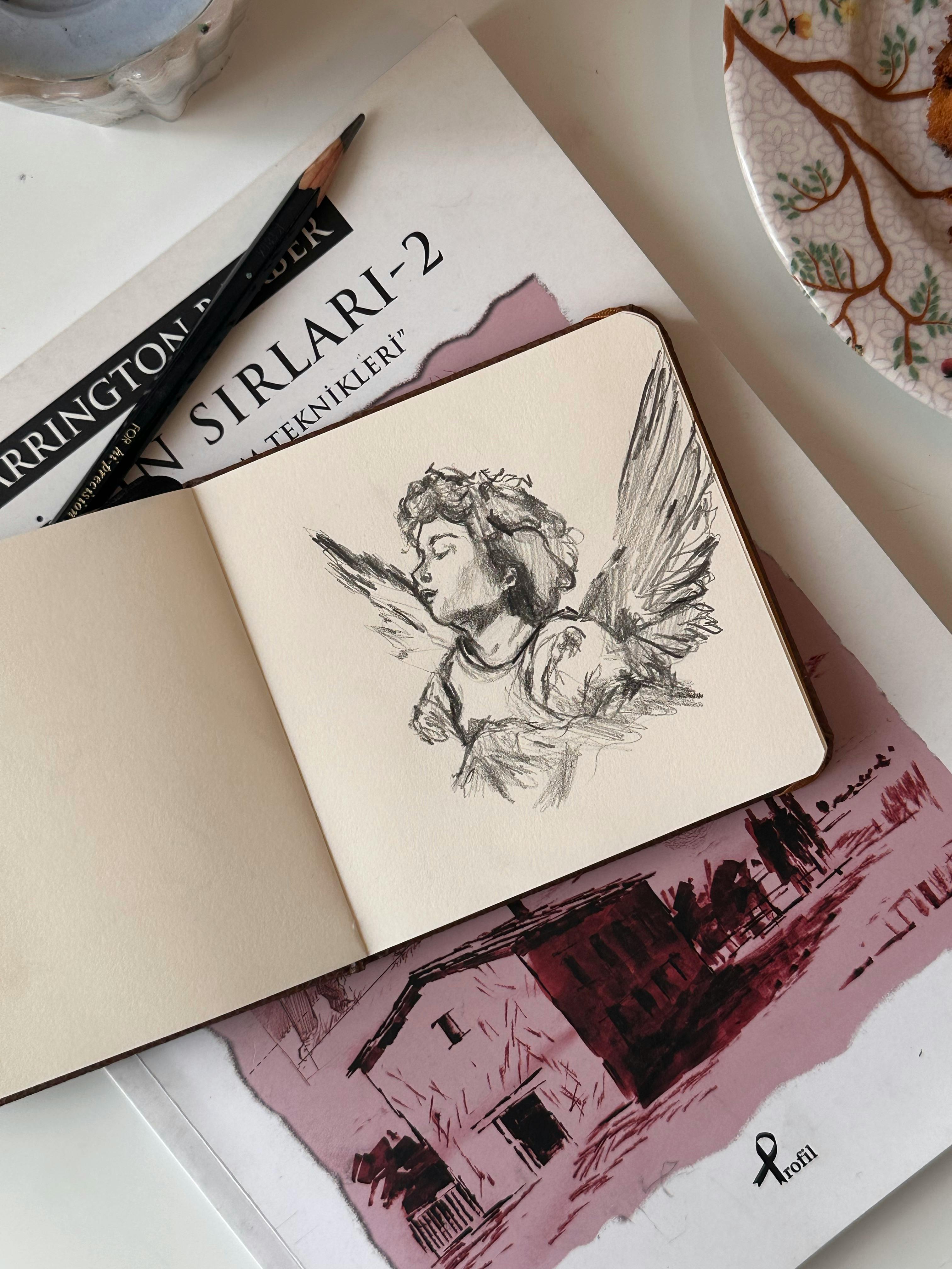 Artistieke Schets Van Engel Op Notitieboekje Met Boek · Gratis stockfoto