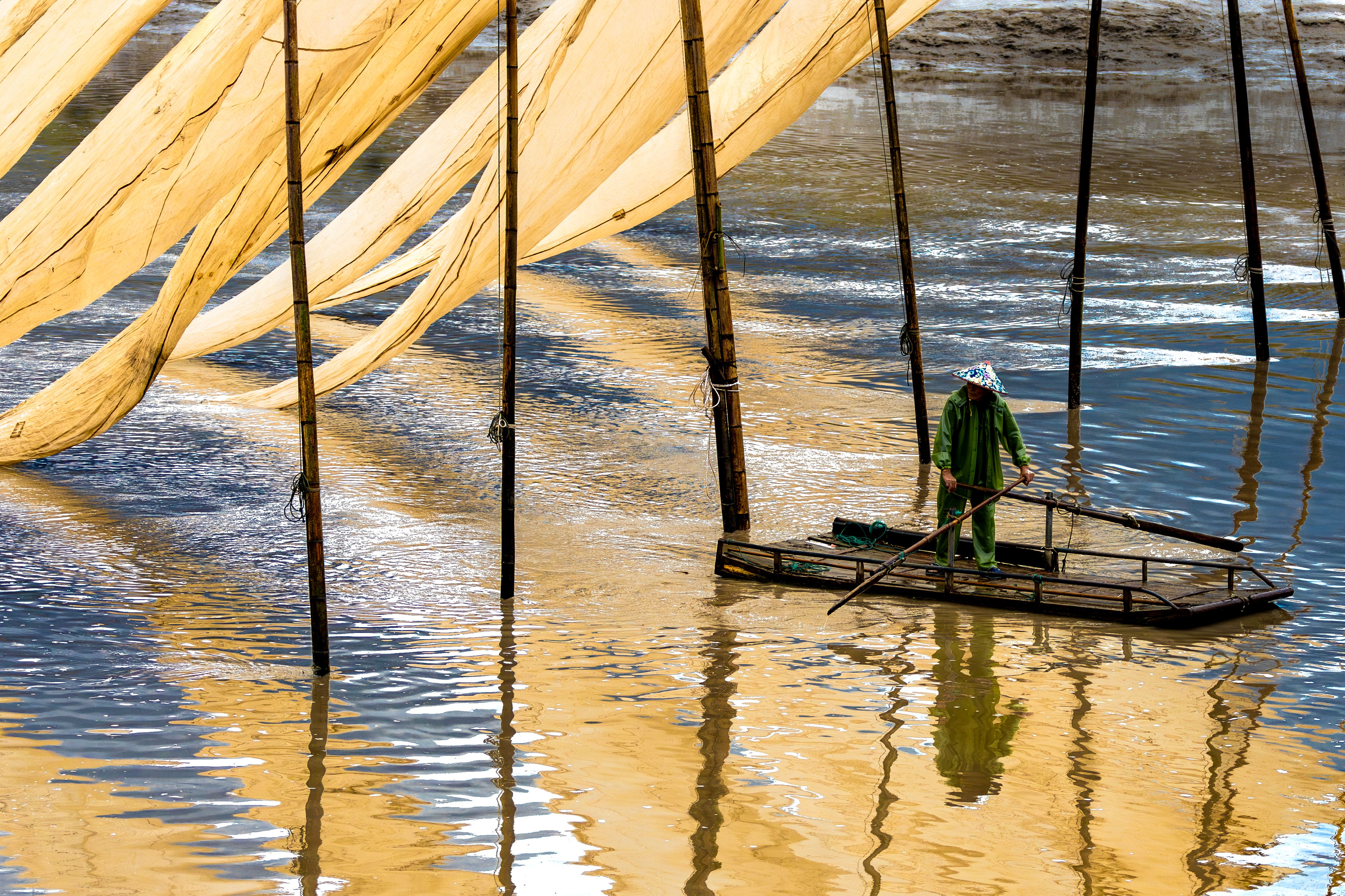 Fisherman Navigating Boat with Sunlit Sails · Free Stock Photo