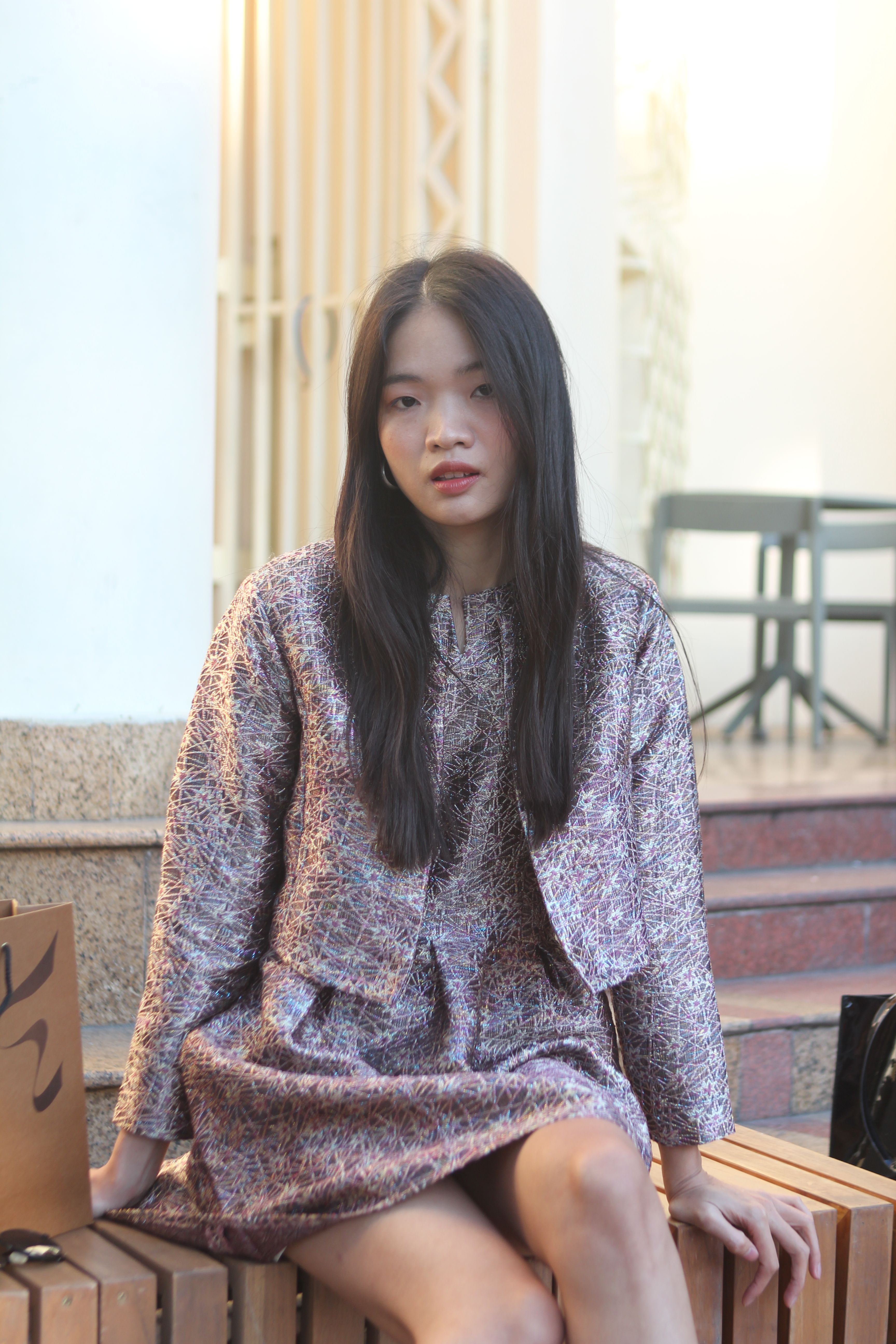 Stylish Woman in Patterned Outfit Sitting Outdoors · Free Stock Photo