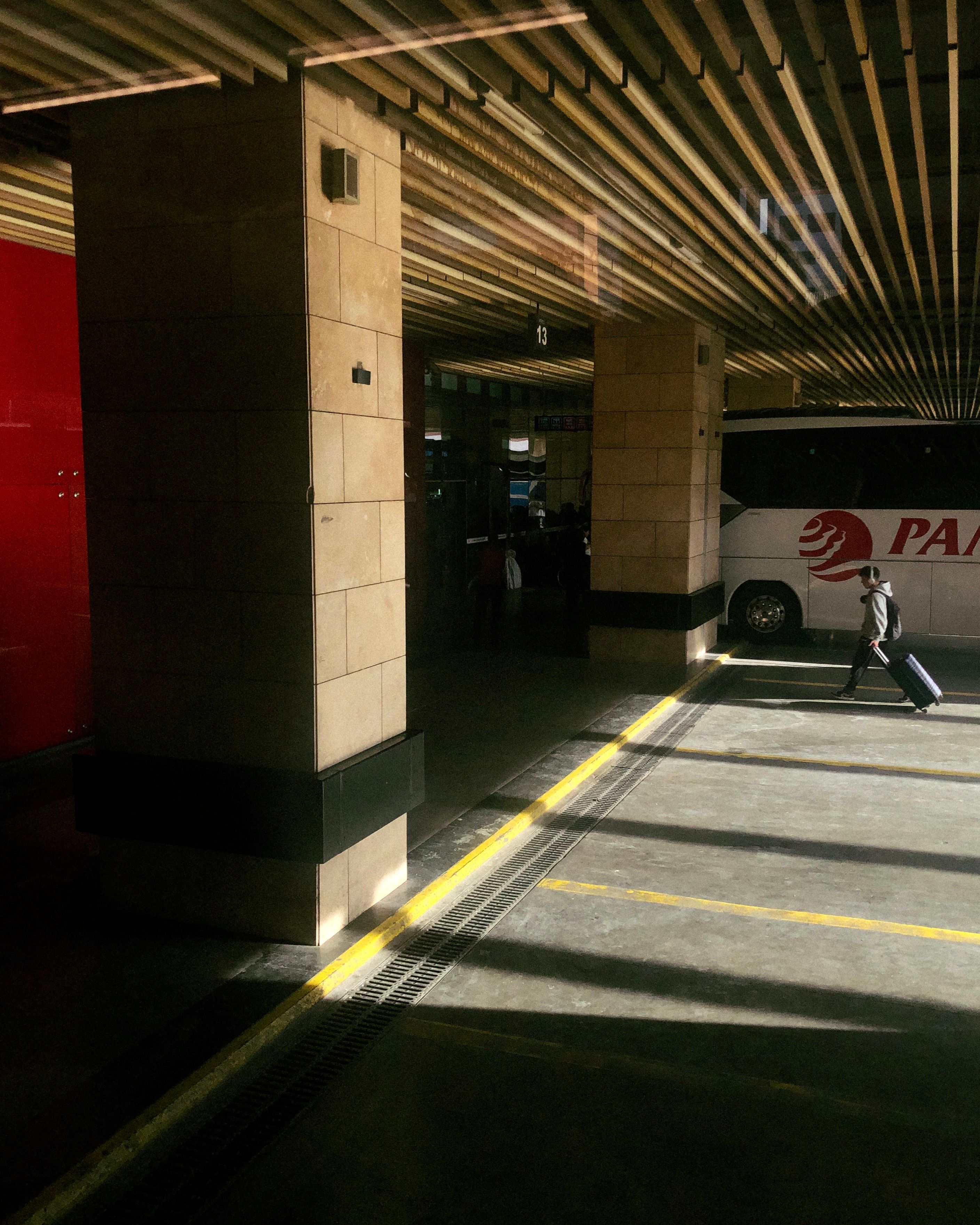 Traveler with luggage at a modern bus terminal · Free Stock Photo