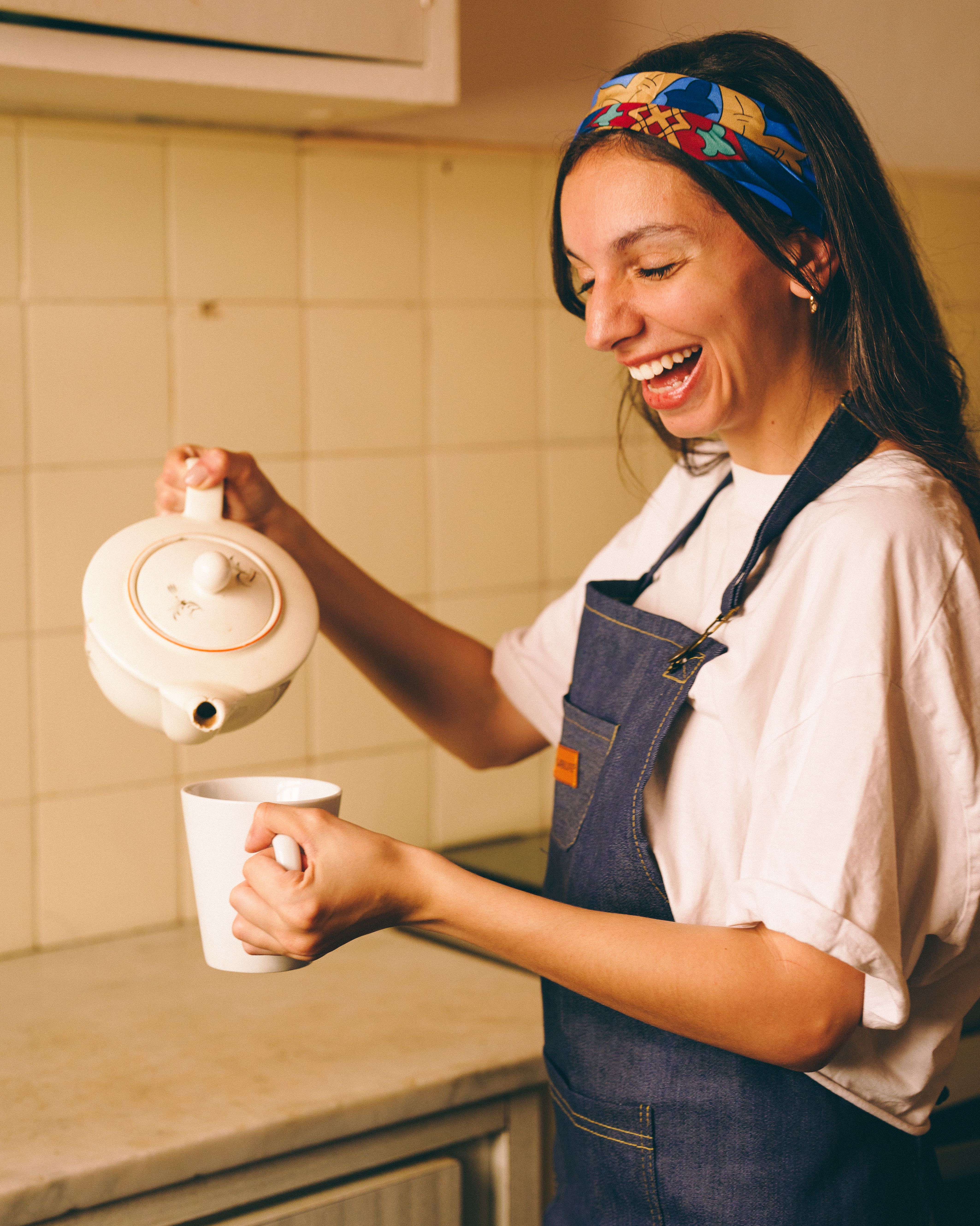 Smiling Woman Pouring Tea in Kitchen Setting · Free Stock Photo