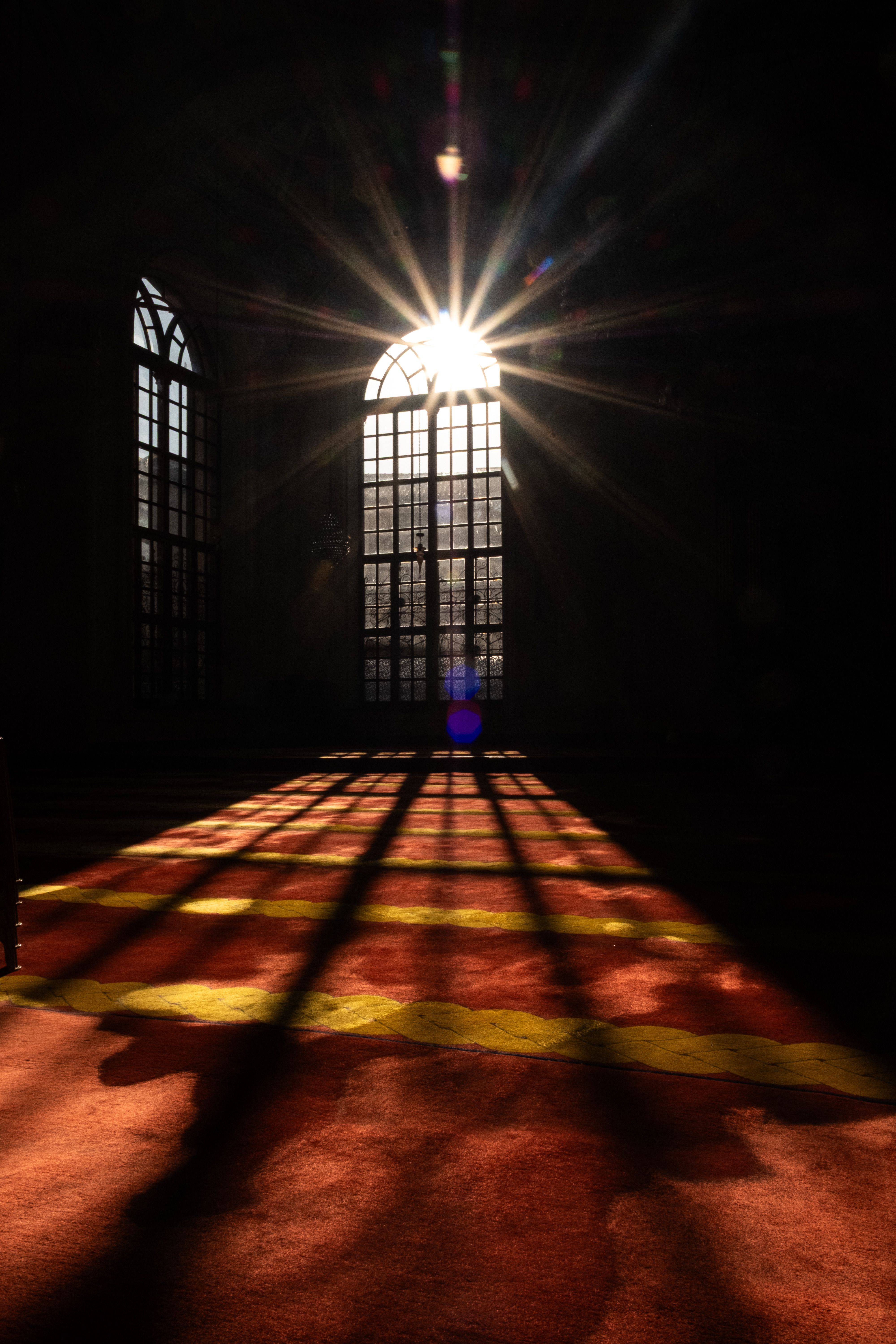 Sunlight streaming through arched windows casting dramatic shadows ...