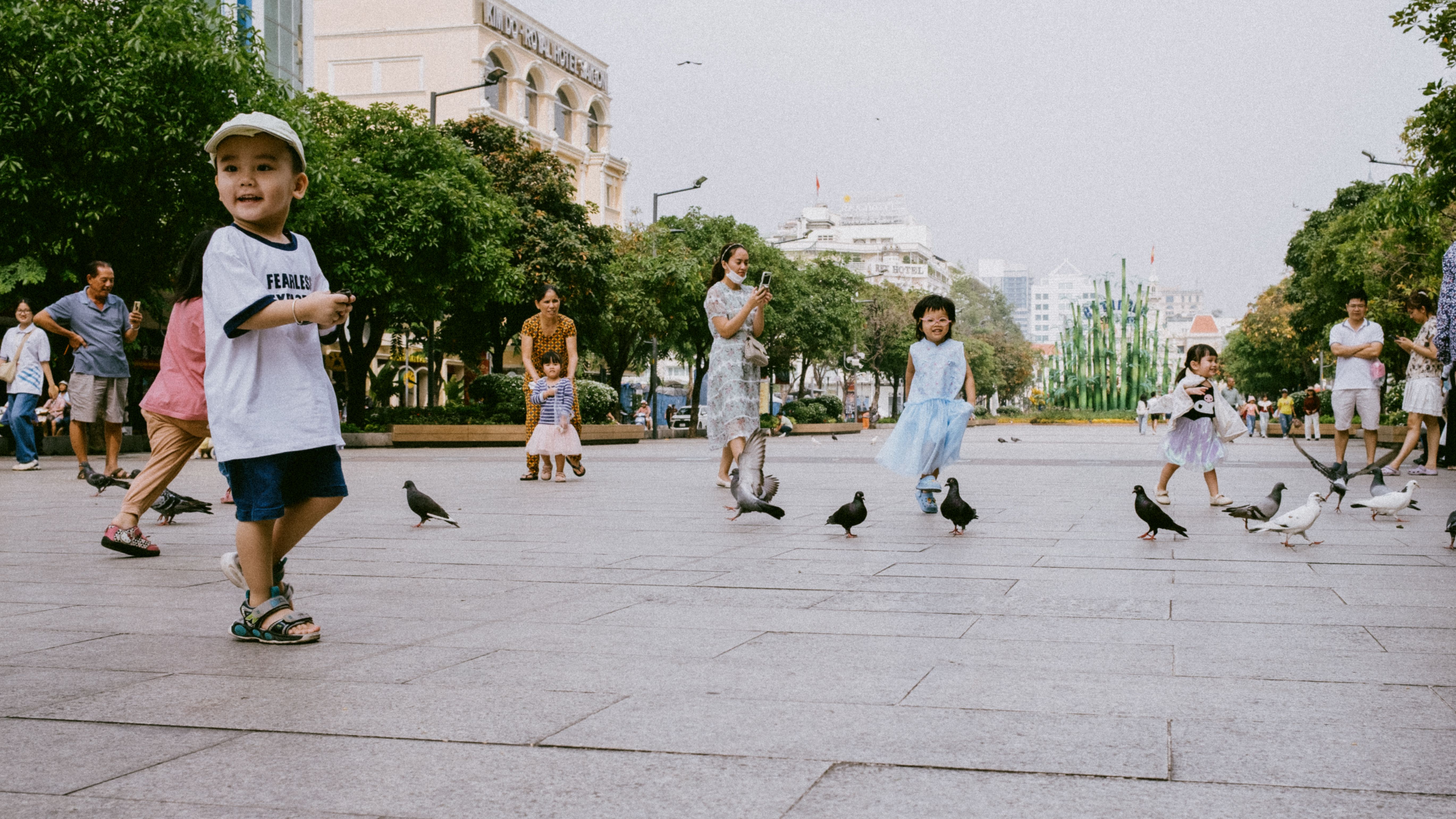 Children playing with pigeons in city square · Free Stock Photo