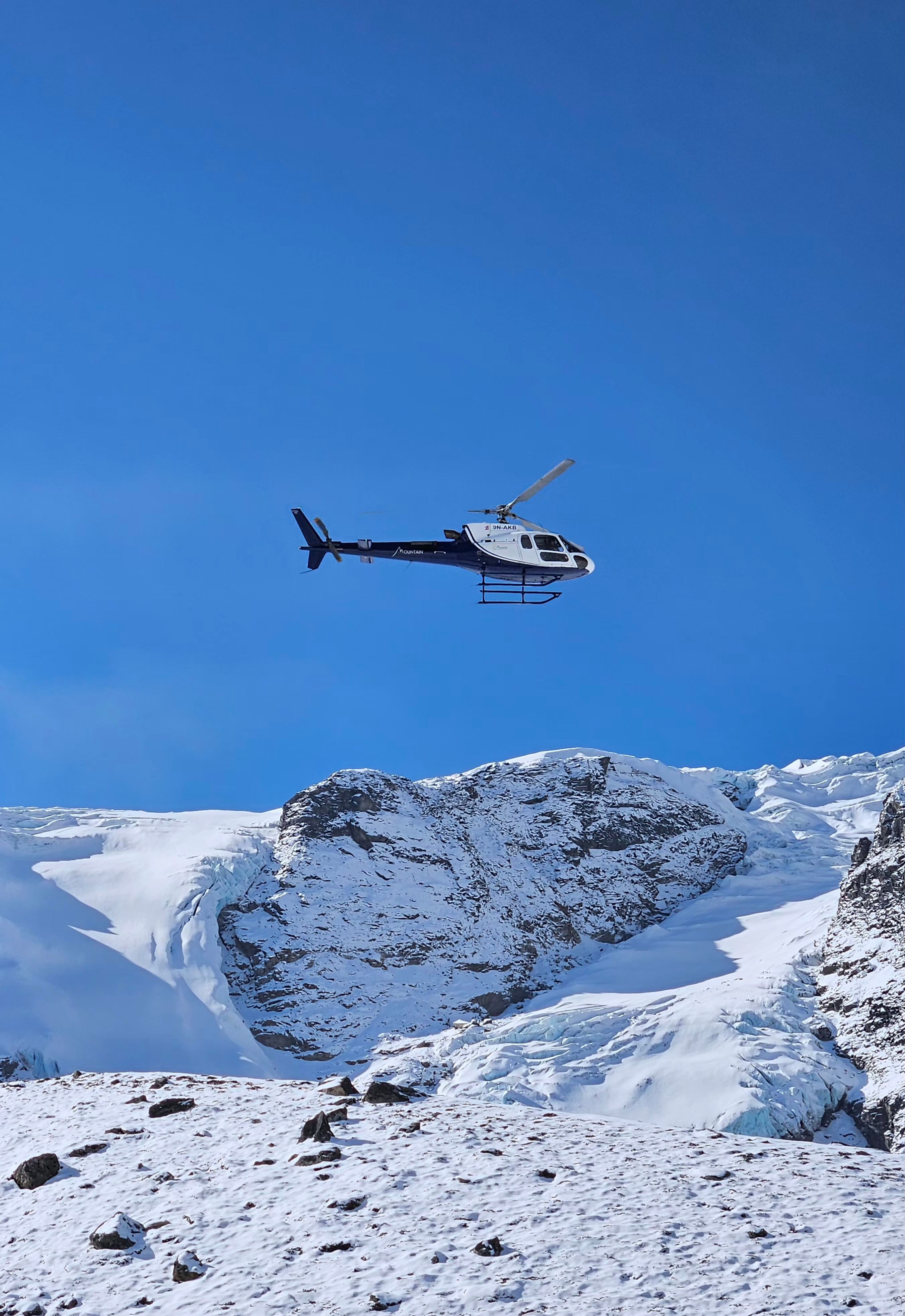 Helicopter Flying Over Snowy Mountain Peaks · Free Stock Photo