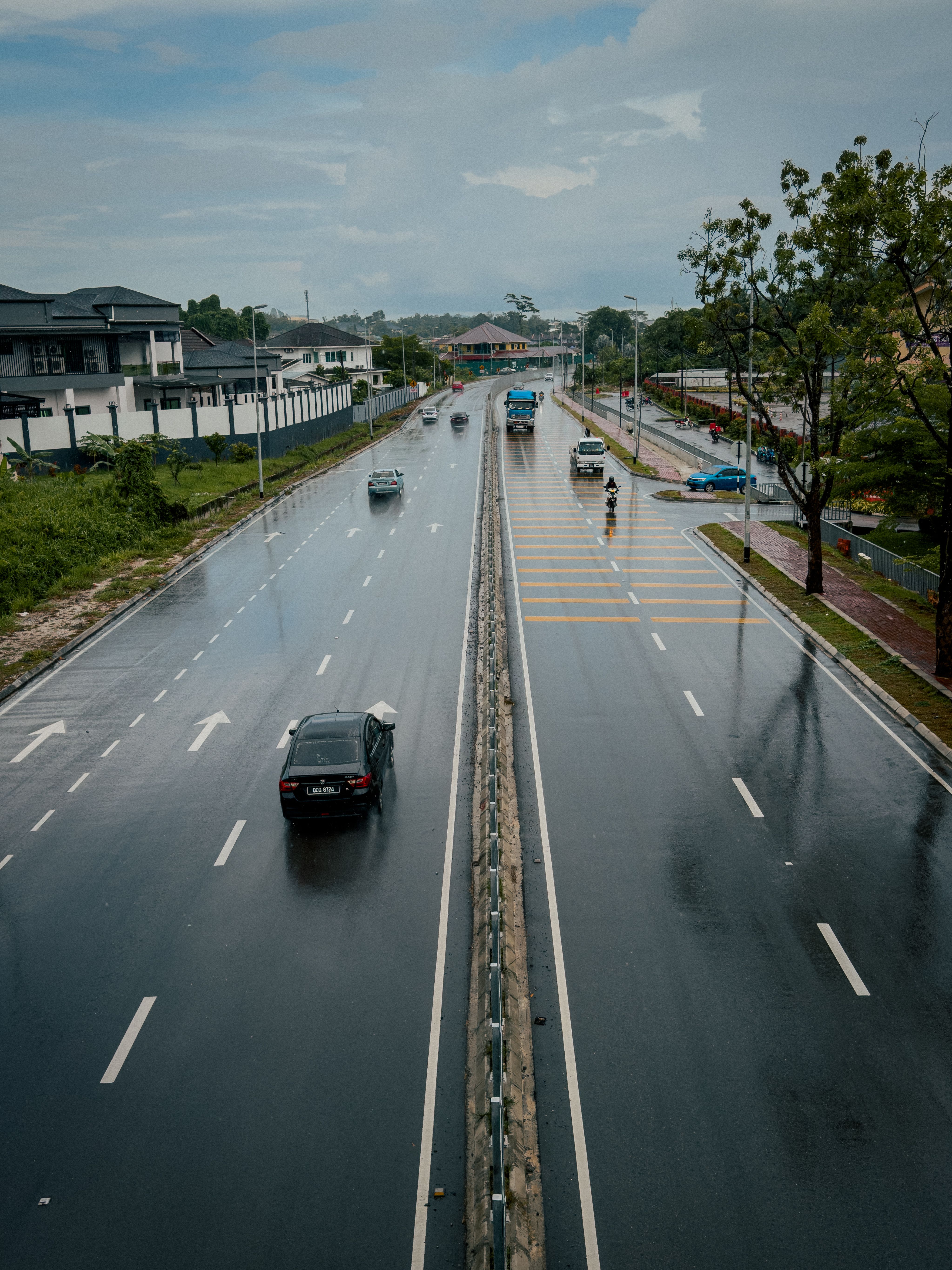 Wet Urban Road with Traffic on Rainy Day · Free Stock Photo