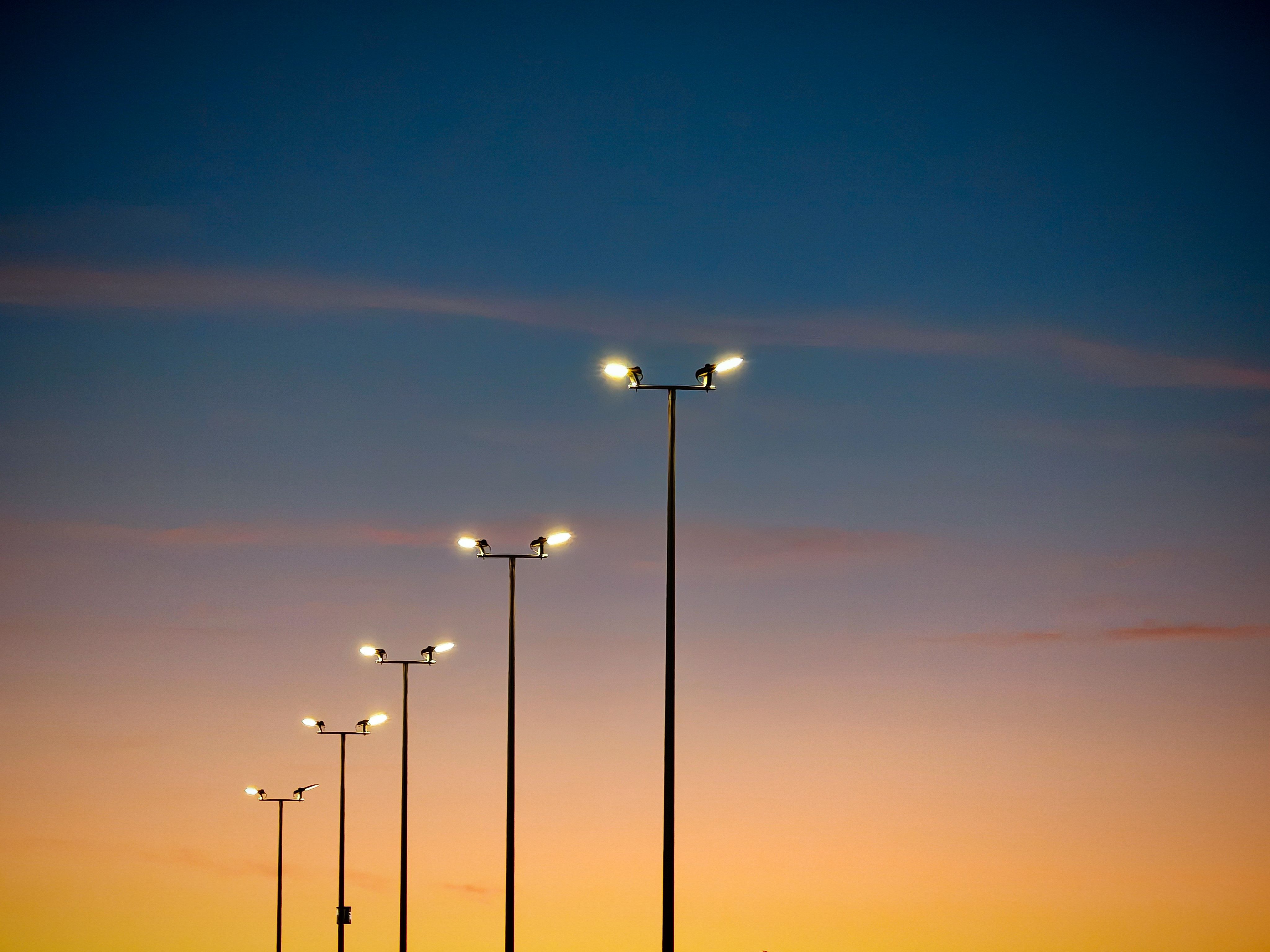 Illuminated Streetlights Against Colorful Sunset · Free Stock Photo