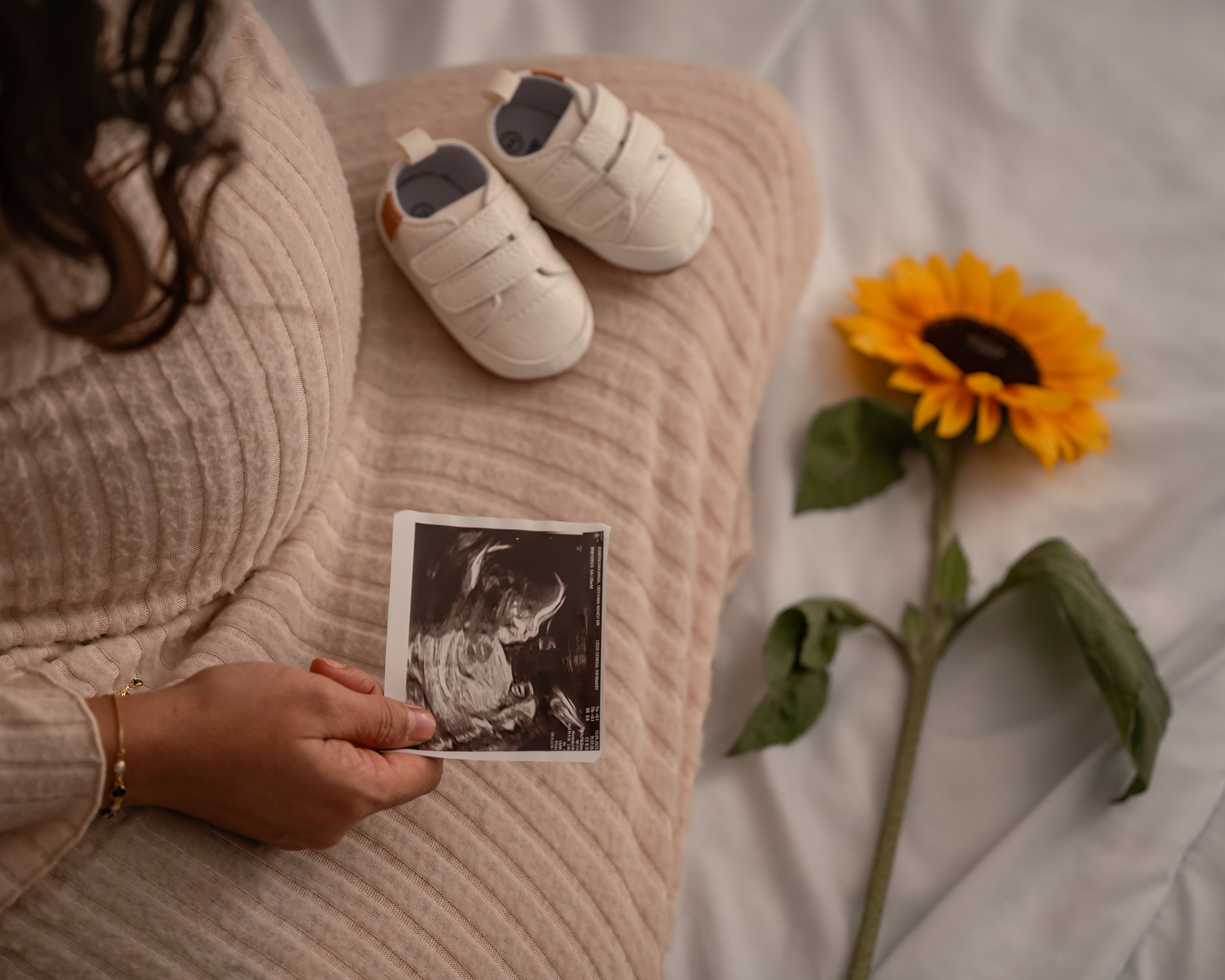 Pregnant Woman Holding Ultrasound with Baby Shoes and Sunflower · Free ...