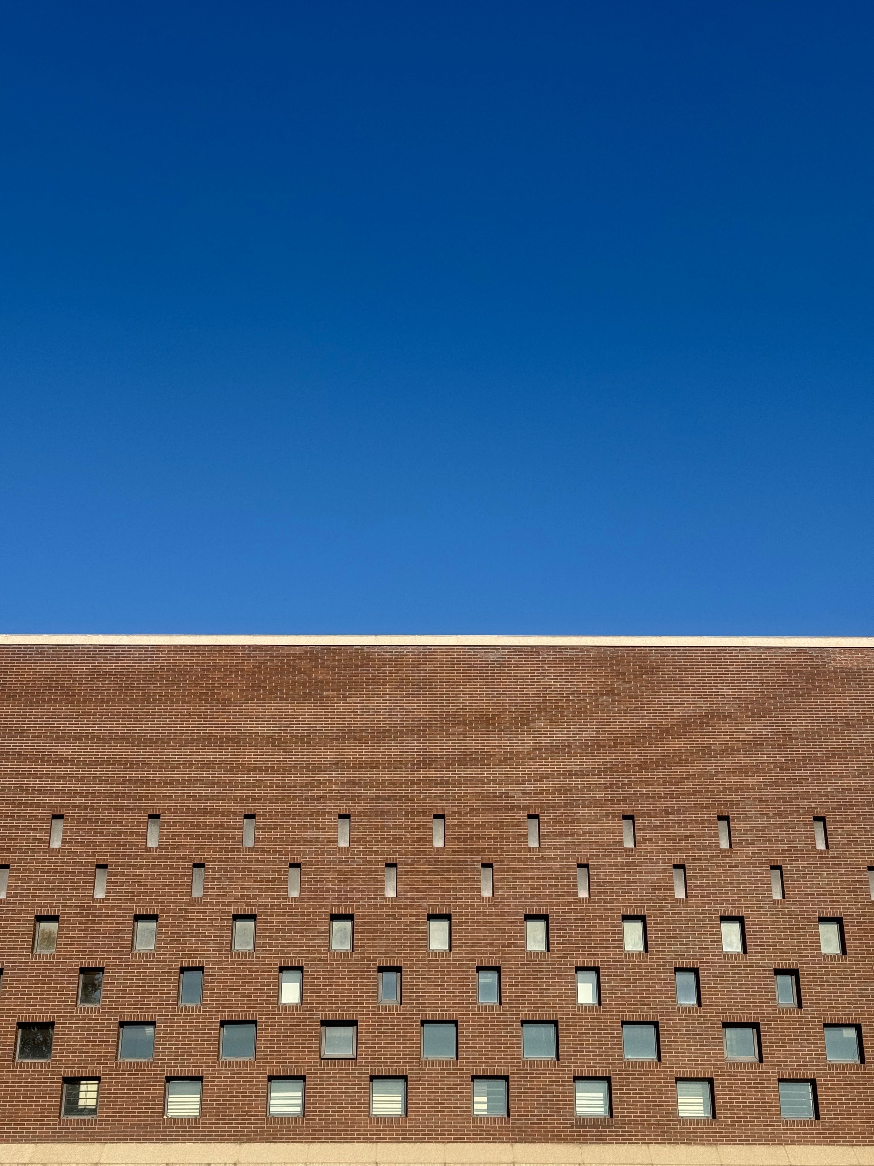 Modern Brick Facade Against Clear Blue Sky · Free Stock Photo