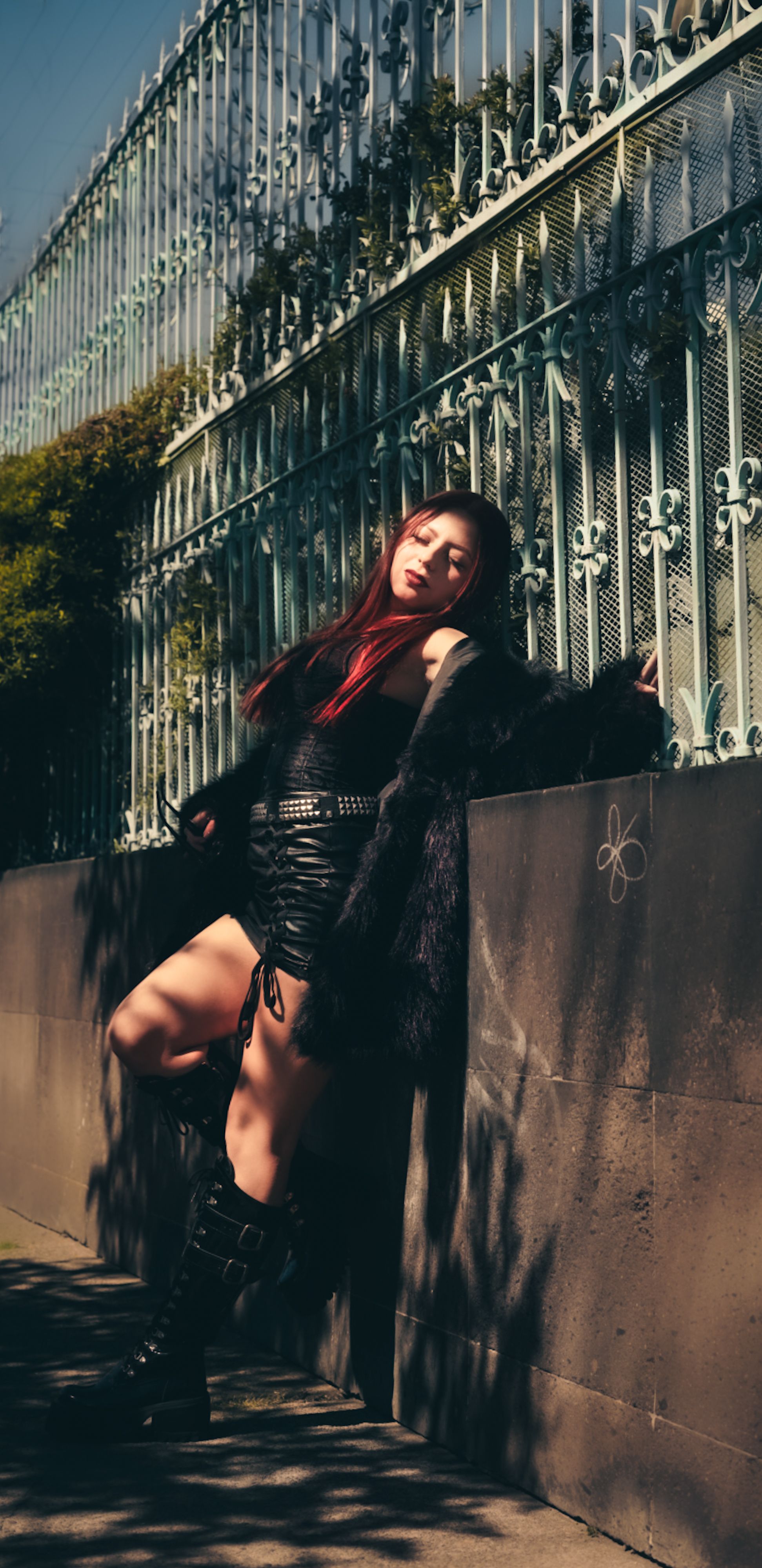 Stylish Woman Posing Against Urban Metal Fence · Free Stock Photo