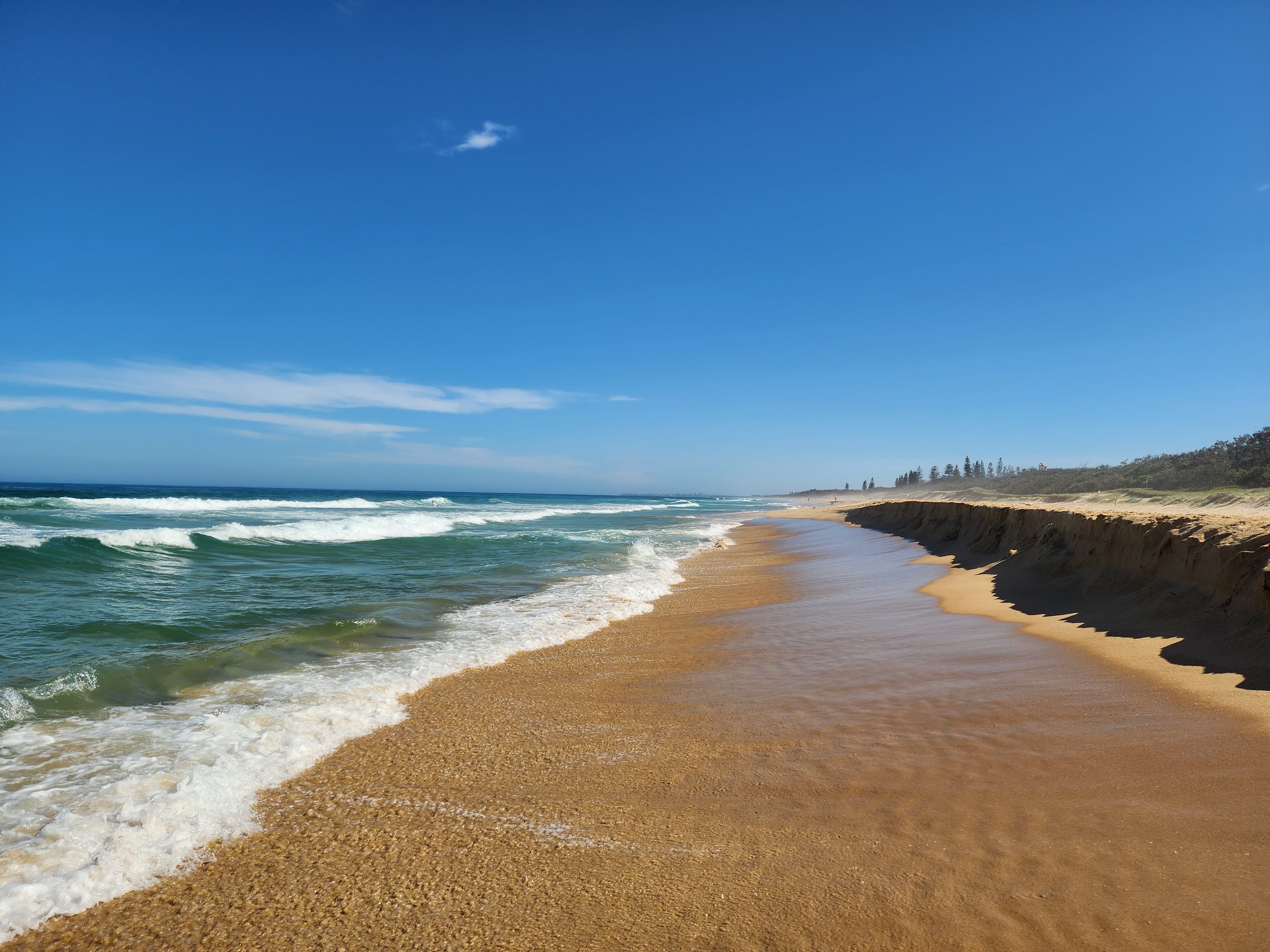 Sandy Beach with Ocean Waves Under Blue Sky · Free Stock Photo