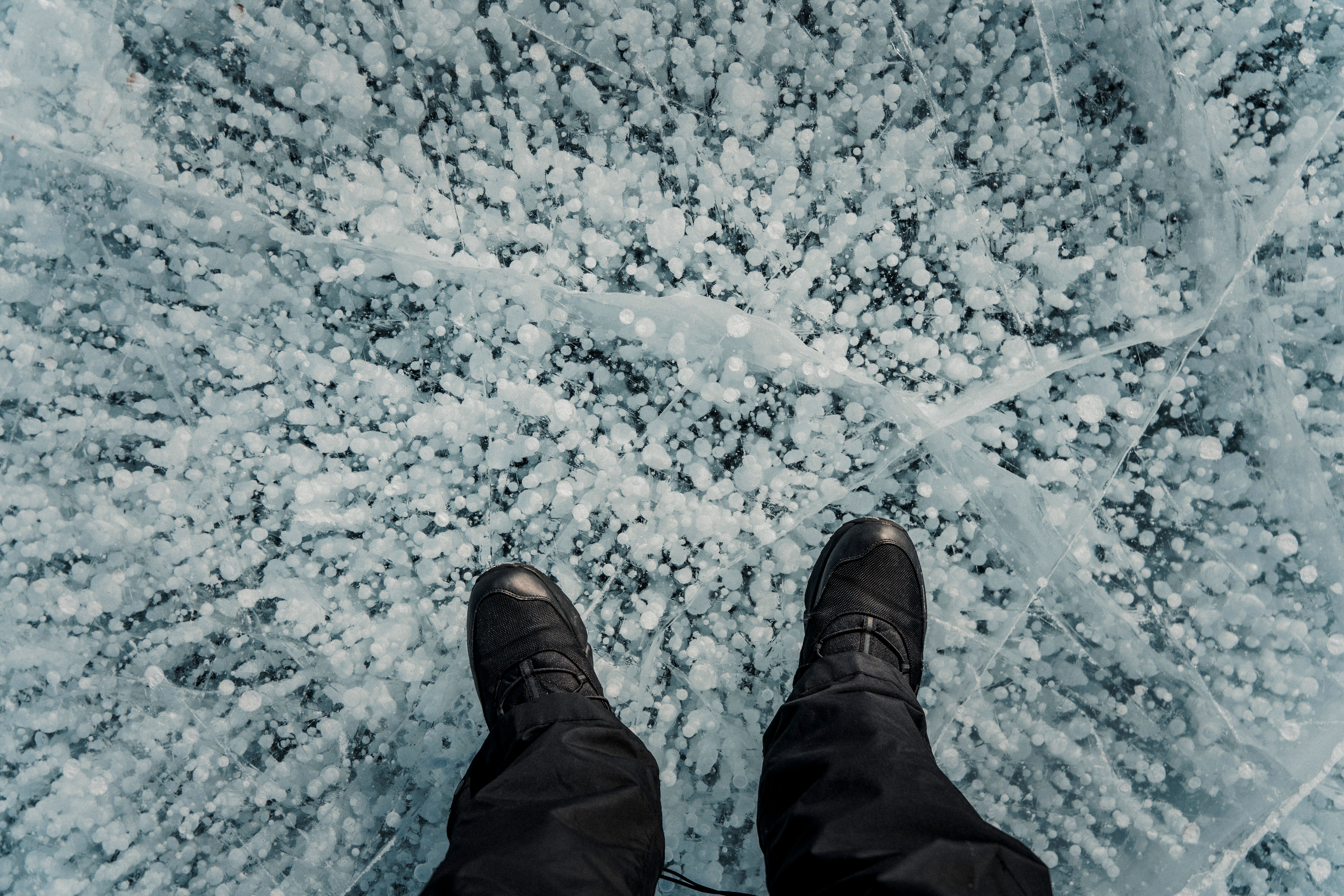 Person standing on frozen ice surface with cracks · Free Stock Photo