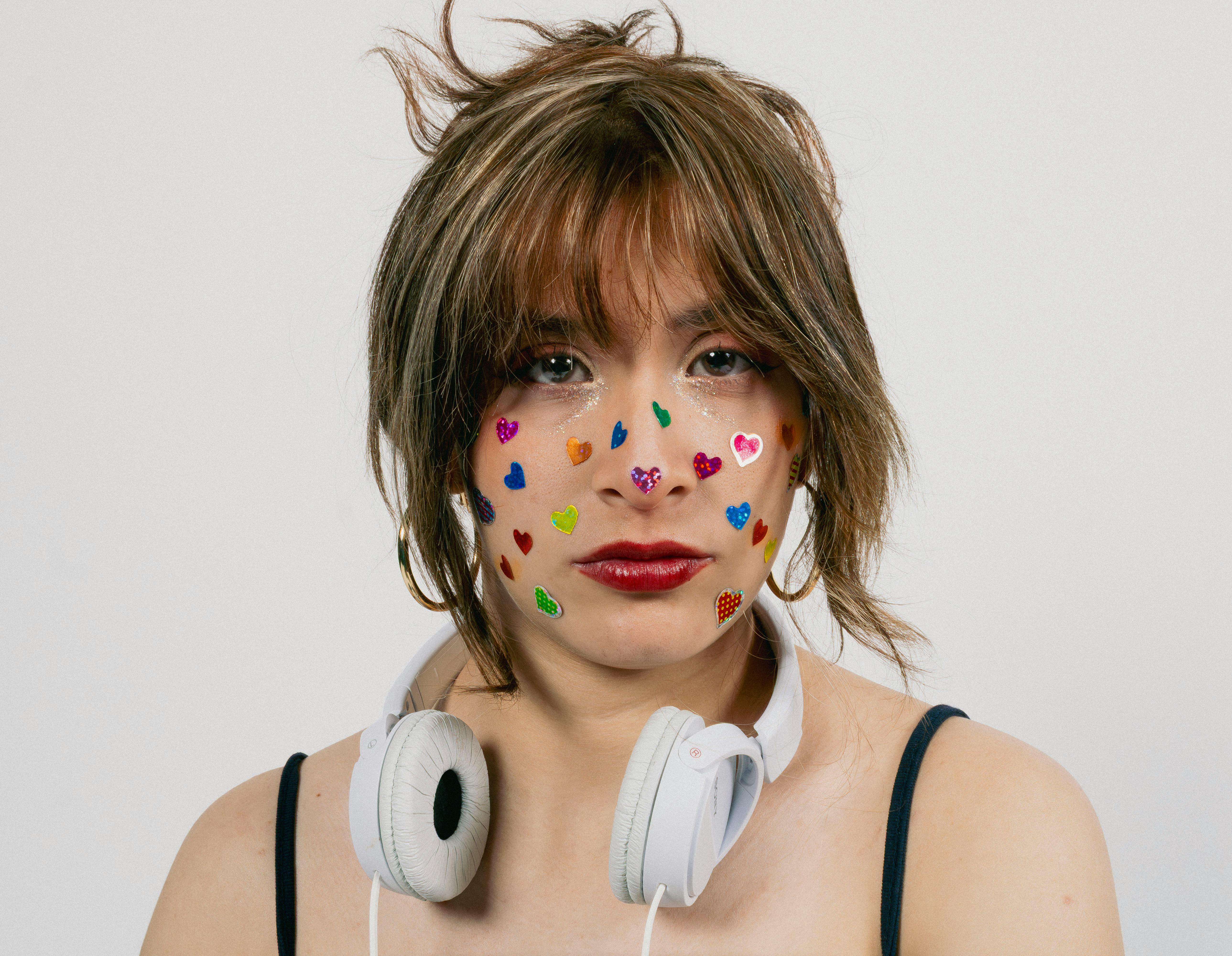 Young Woman with Colorful Face Stickers and Headphones · Free Stock Photo