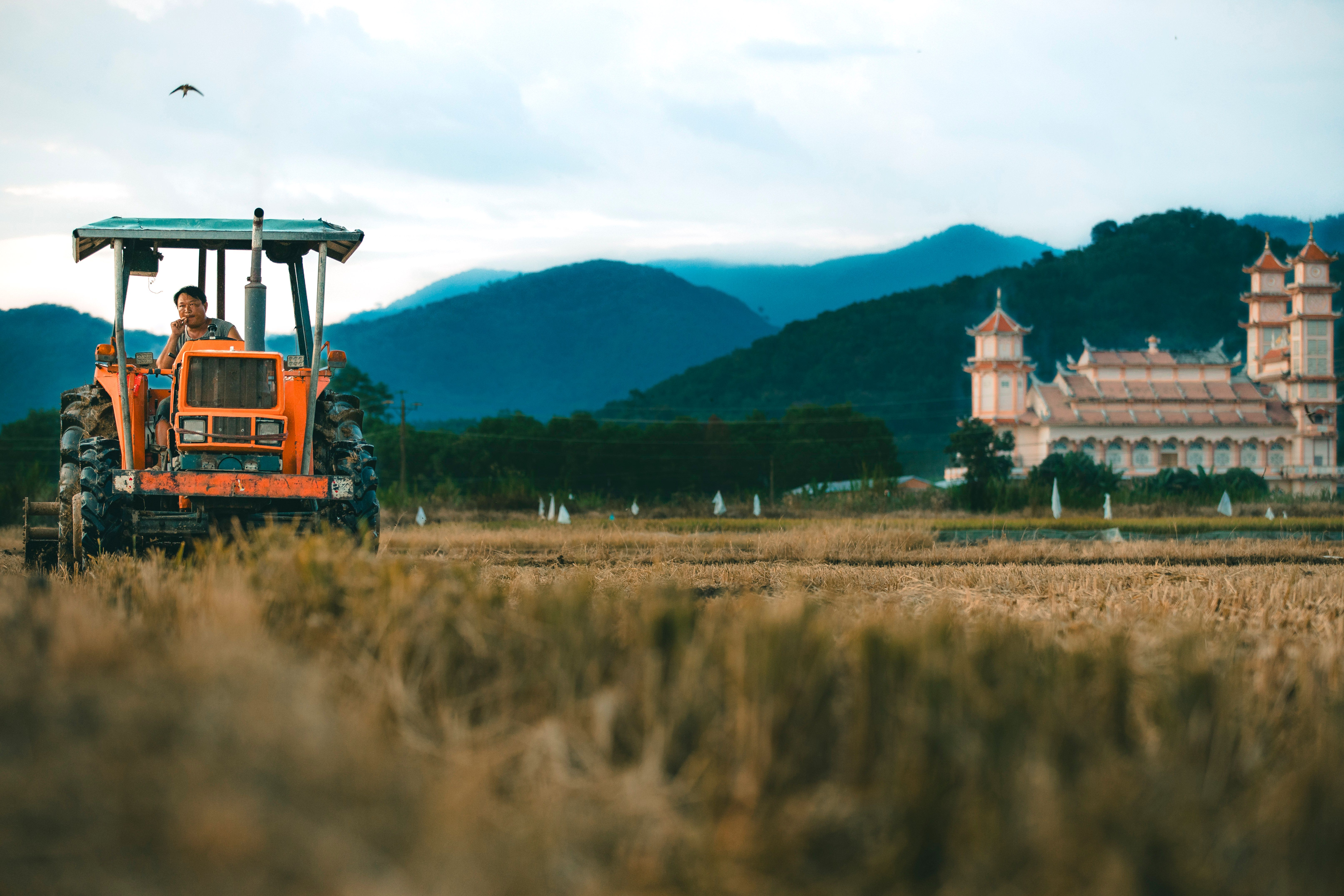 Farmer Operating Tractor in Scenic Farmland Landscape · Free Stock Photo