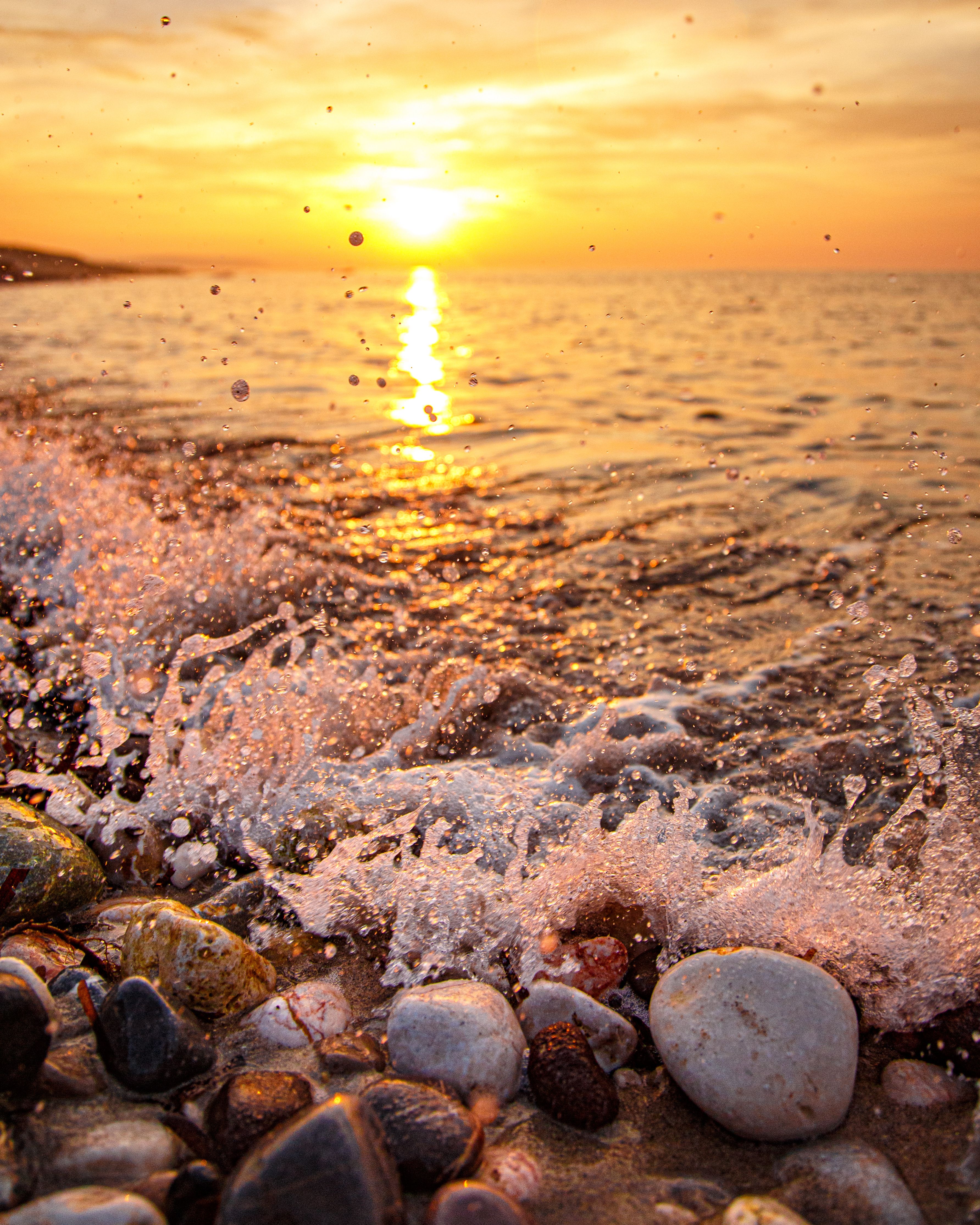 Vibrant Ocean Waves at Sunset with Pebble Beach · Free Stock Photo