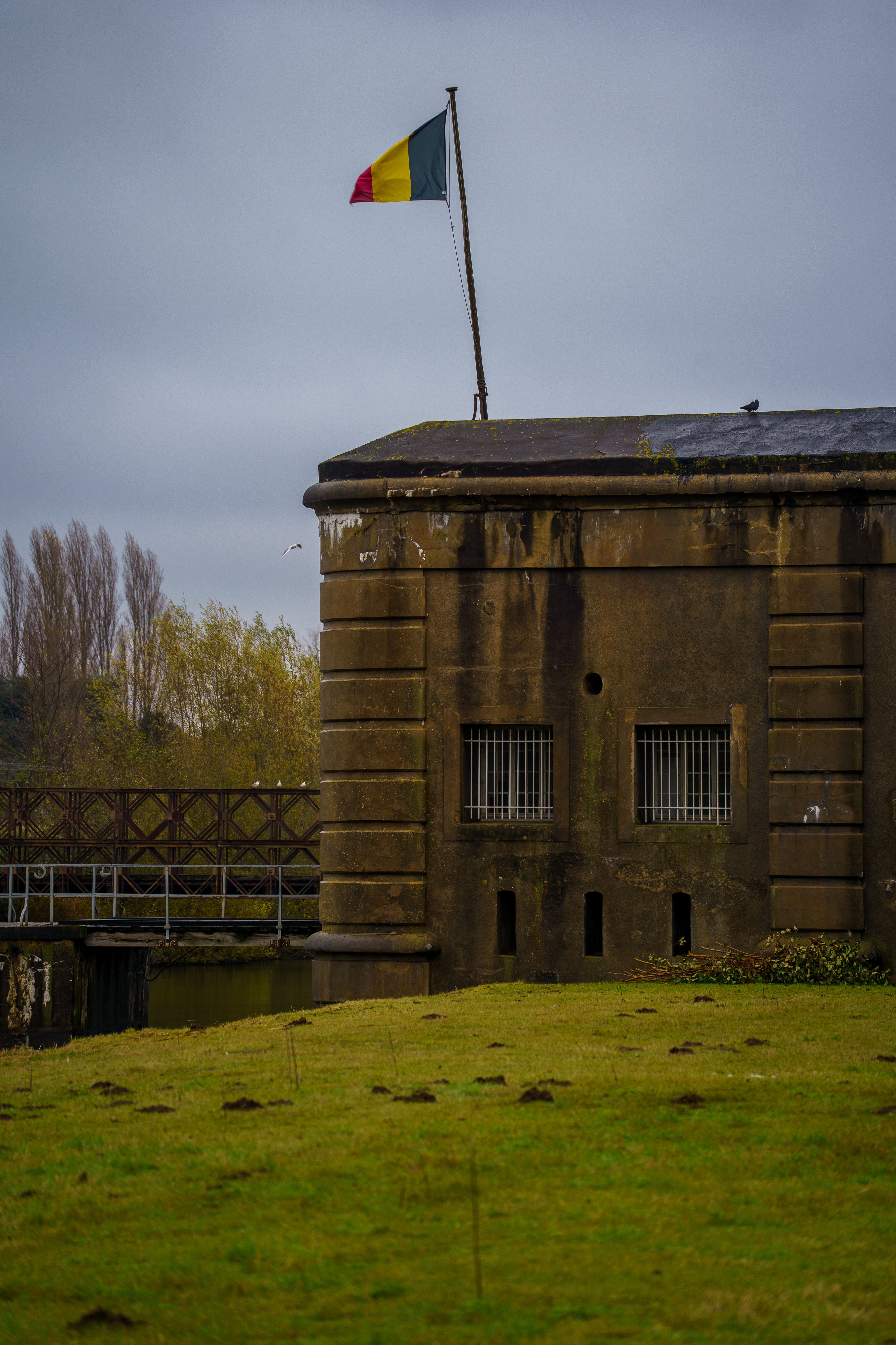 Historic Belgian fort with flag on overcast day · Free Stock Photo