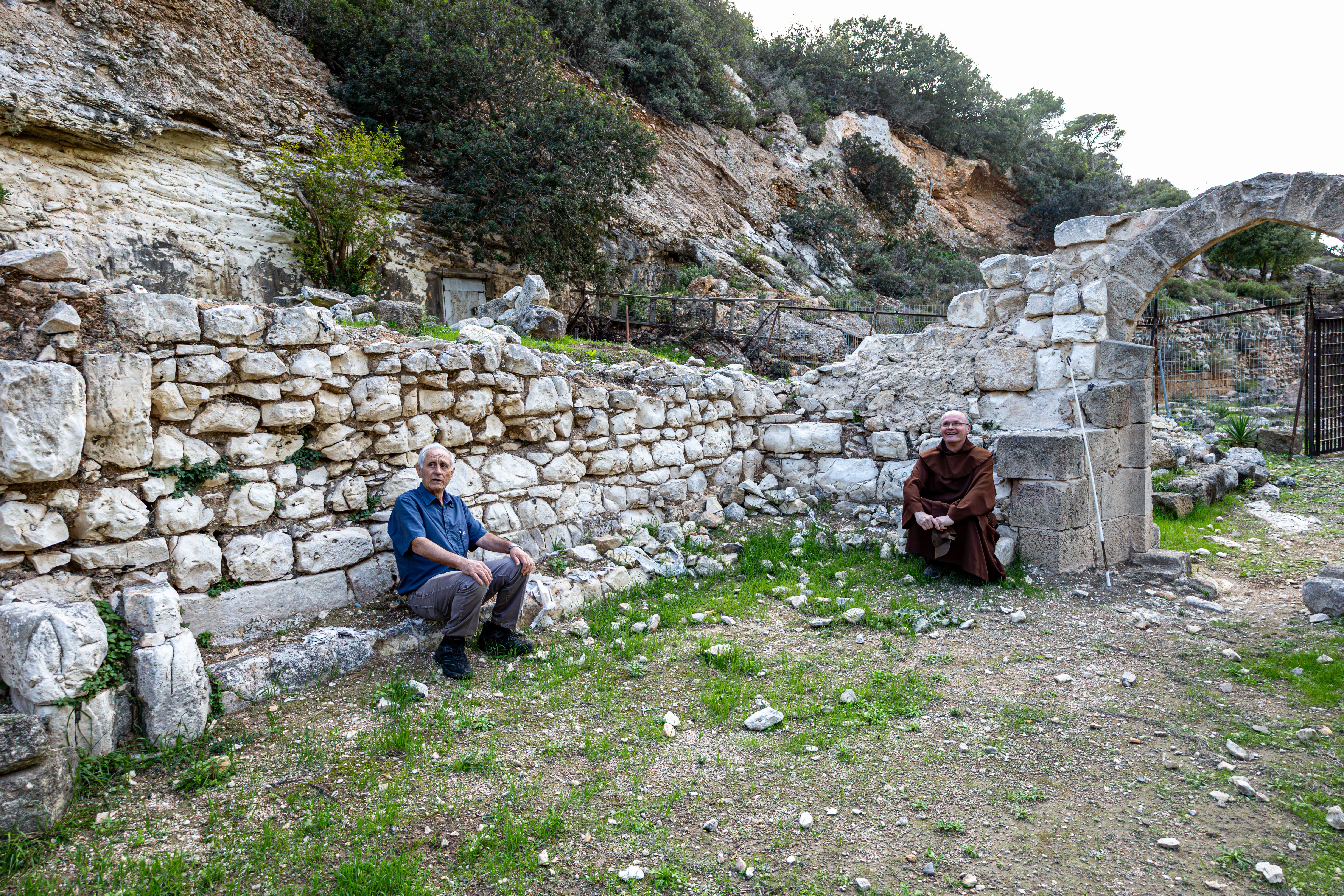 Two Men Sitting by Ancient Stone Ruins Outdoors · Free Stock Photo