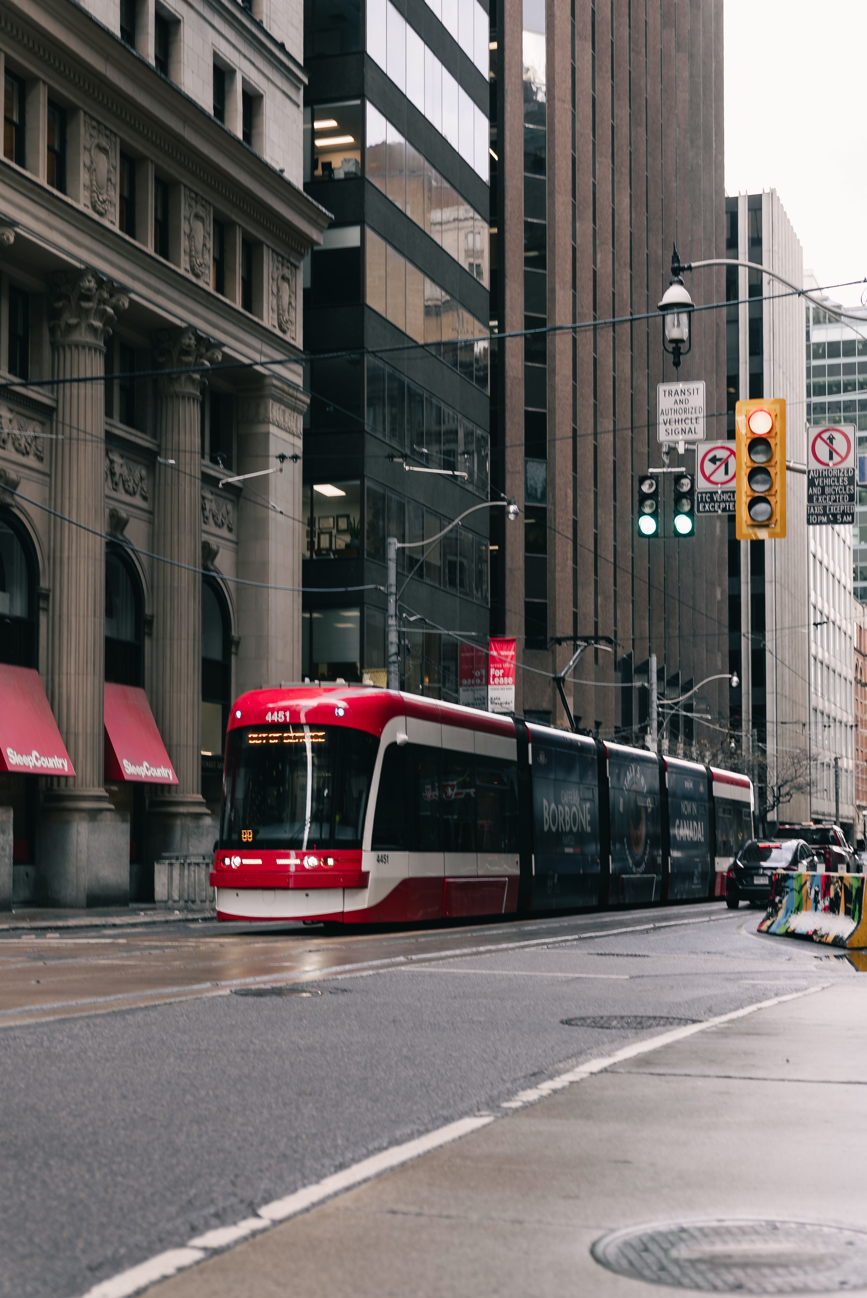 Red Streetcar Passing Through Urban Cityscape · Free Stock Photo