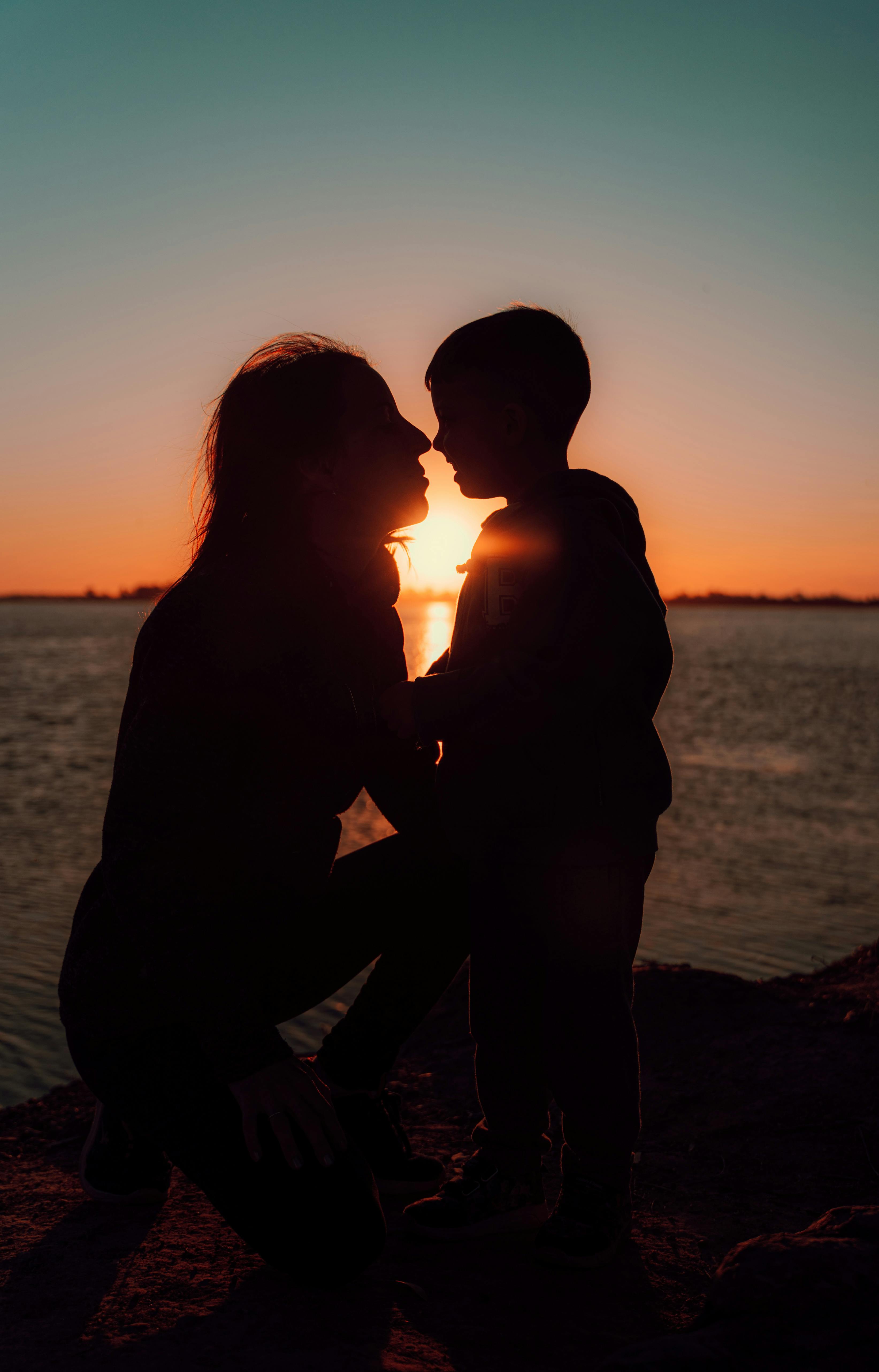Mother and Child Silhouette at Sunset by the Sea · Free Stock Photo