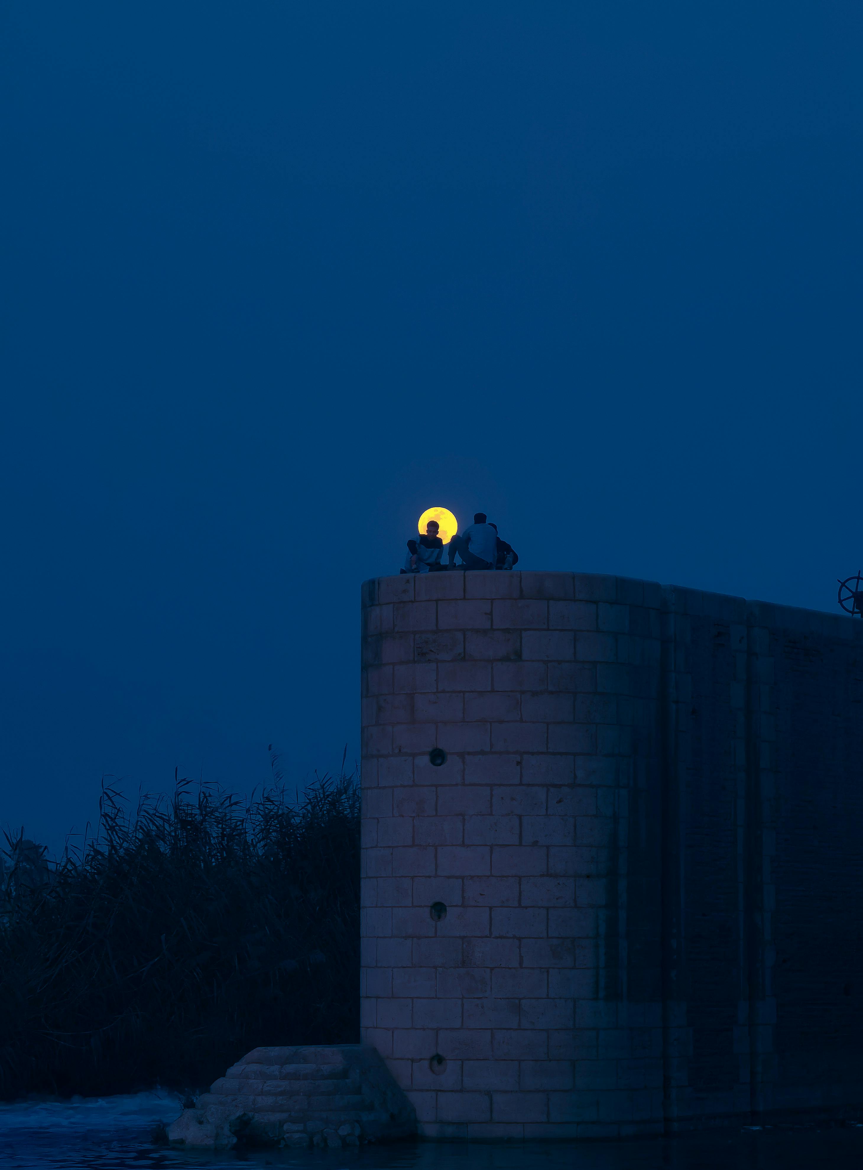 Personas Silueteadas Por La Luna Llena Sobre Una Estructura De Piedra ...