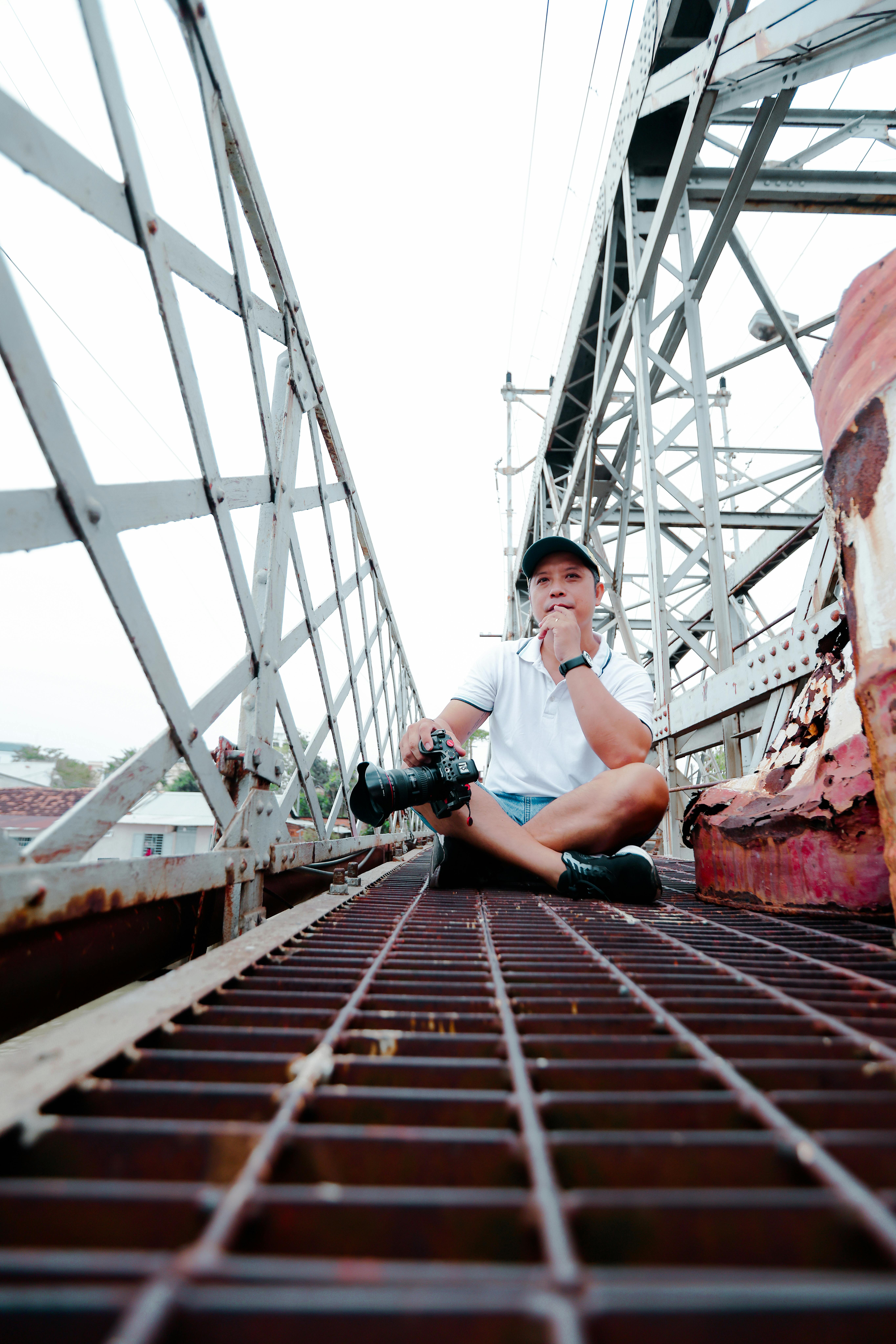 Person Sitting on Industrial Metal Structure Outdoors · Free Stock Photo