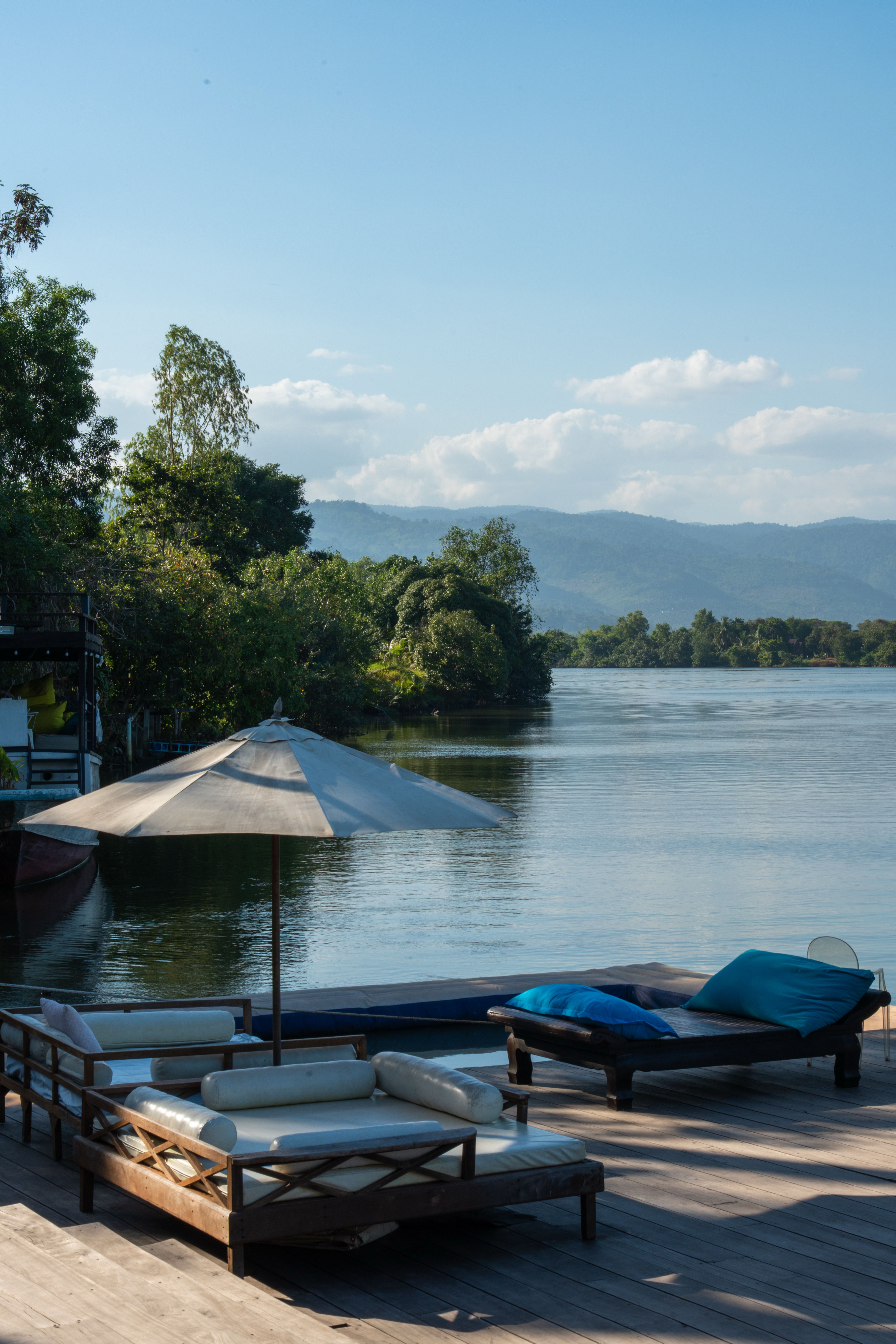 Tranquil Riverside Deck with Lounge Chairs and Umbrella · Free Stock Photo