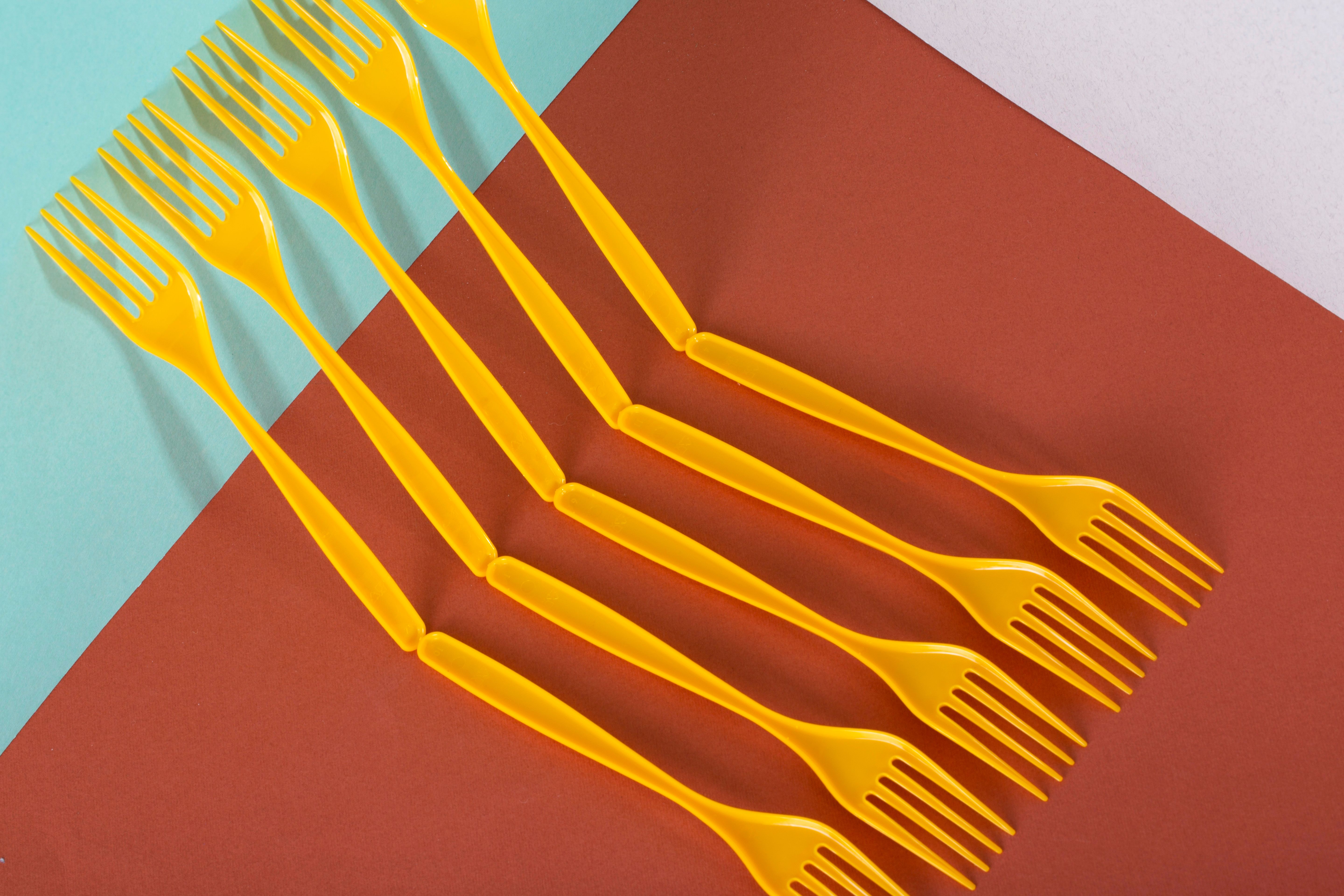 Bright Yellow Plastic Forks on Geometric Background · Free Stock Photo