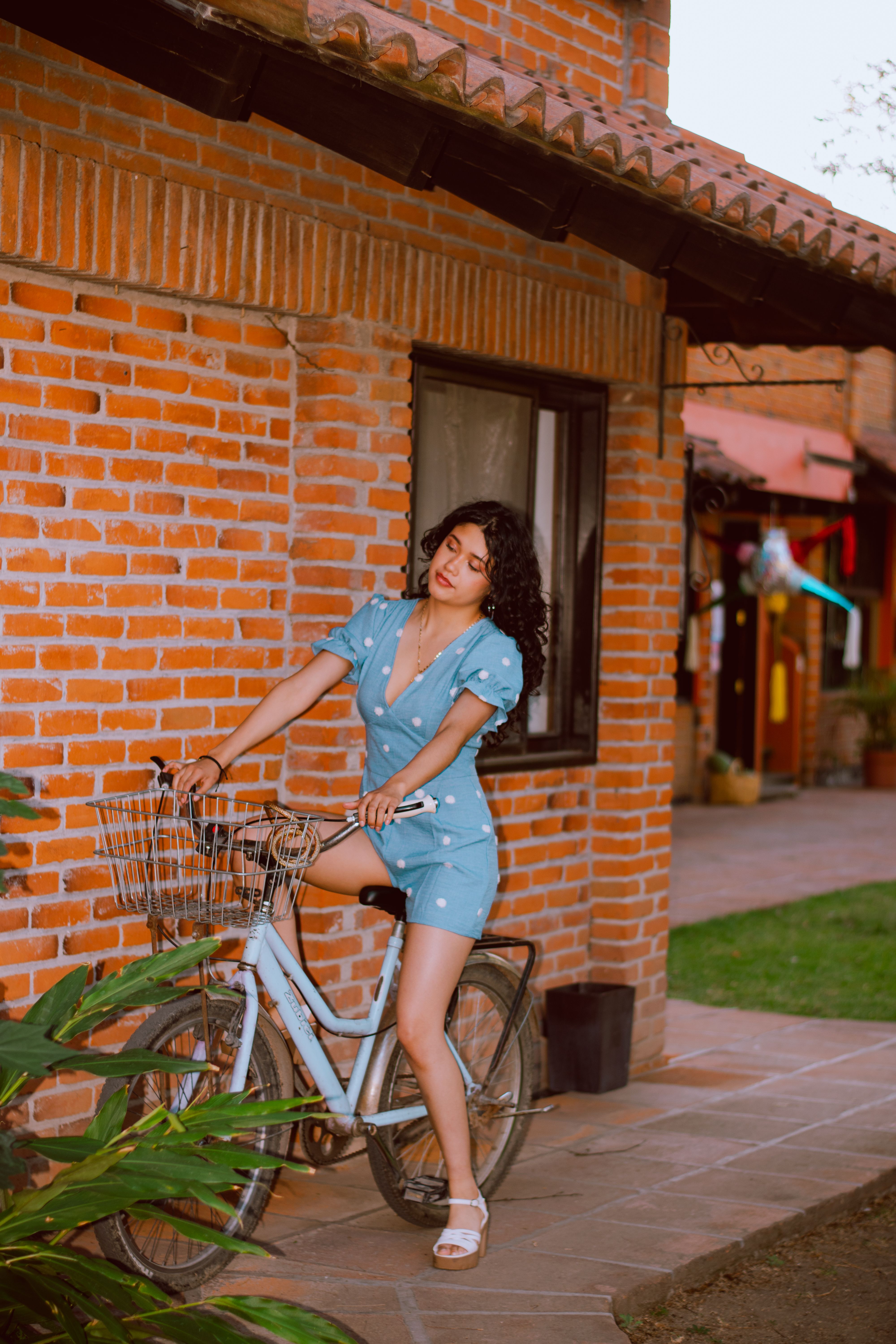 Young woman with bicycle against brick house · Free Stock Photo