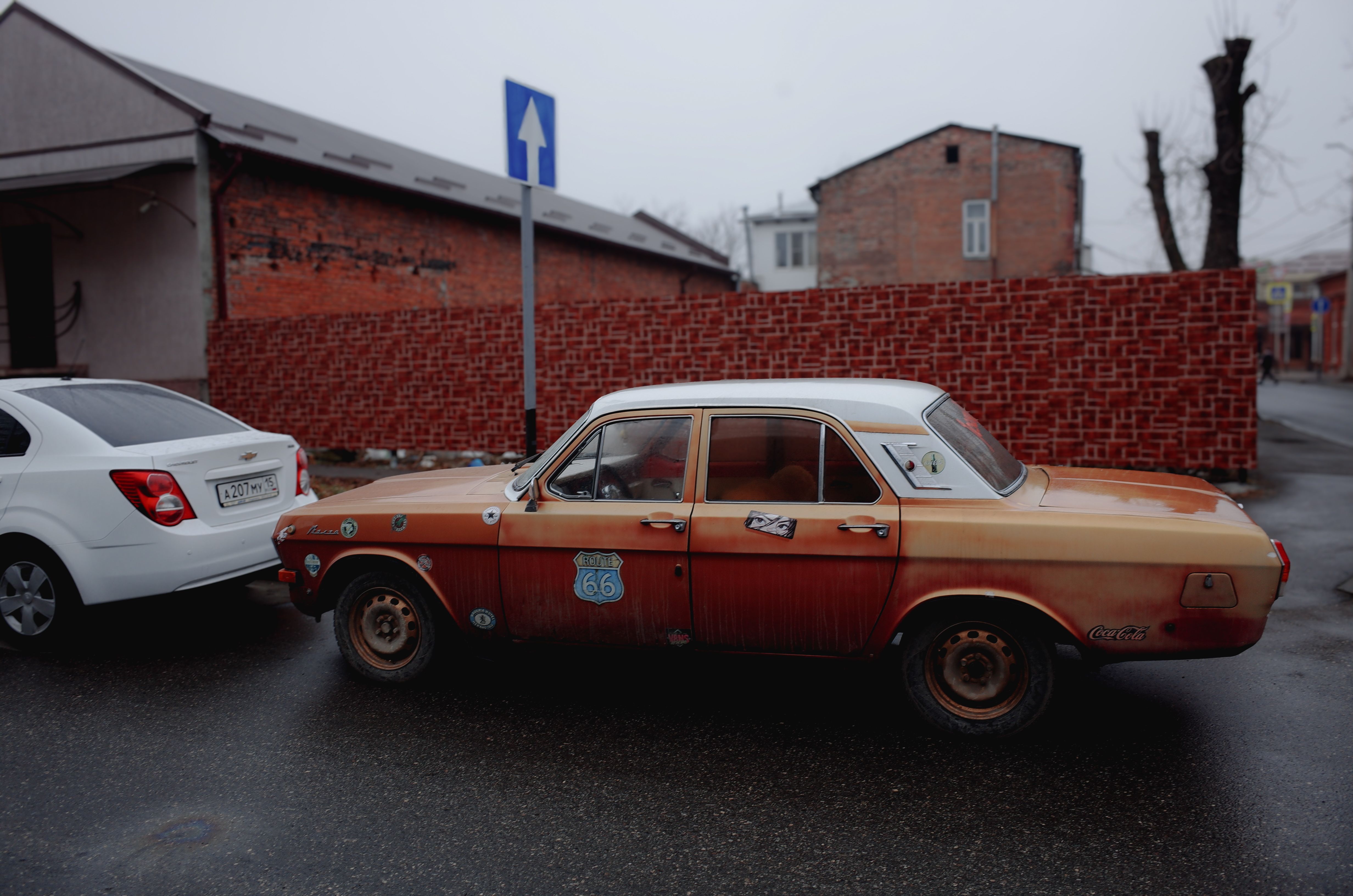 Vintage Car on Wet Street with Brick Wall · Free Stock Photo