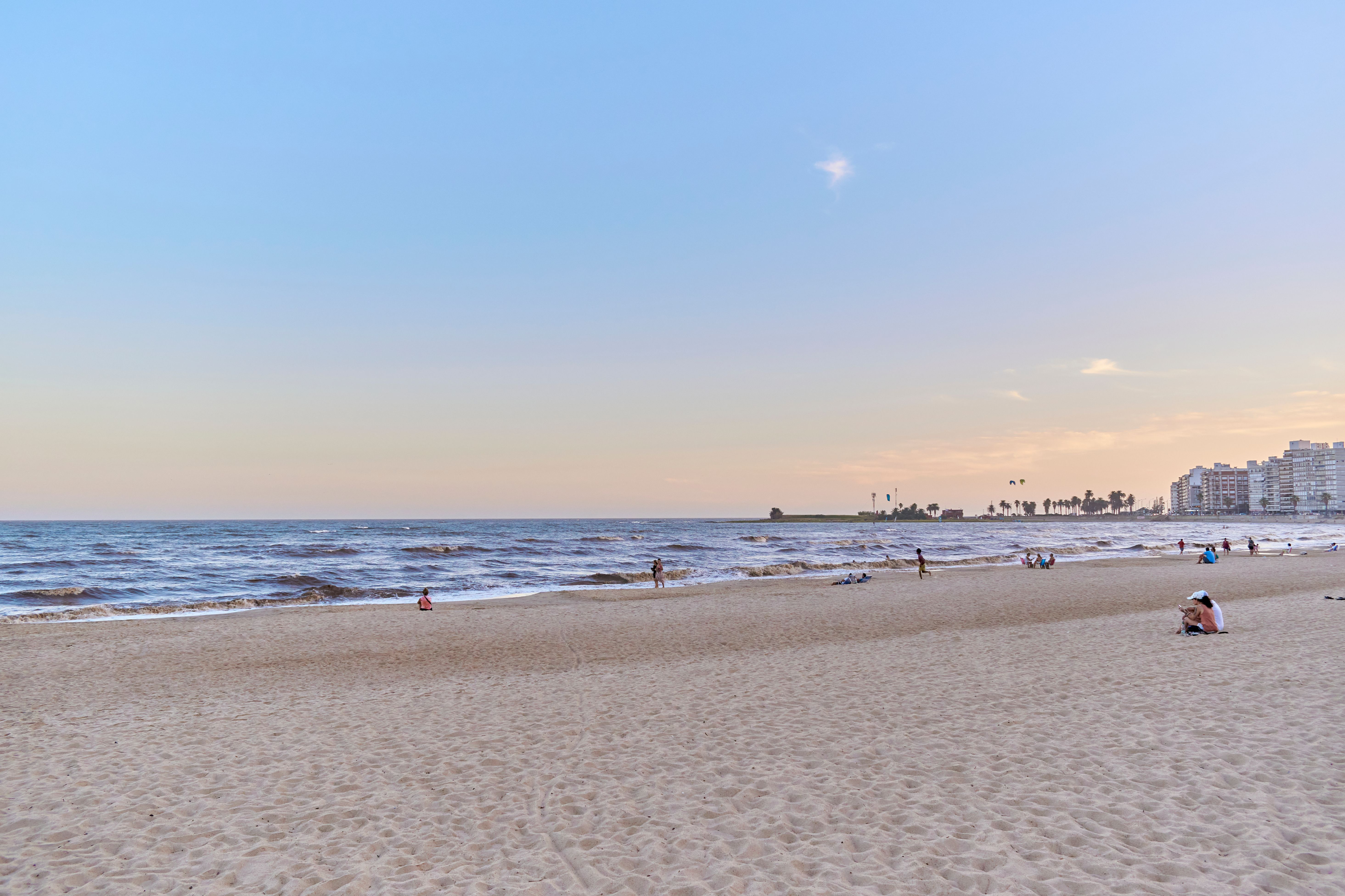 Serene Beachfront at Sunset with Distant Skyline · Free Stock Photo