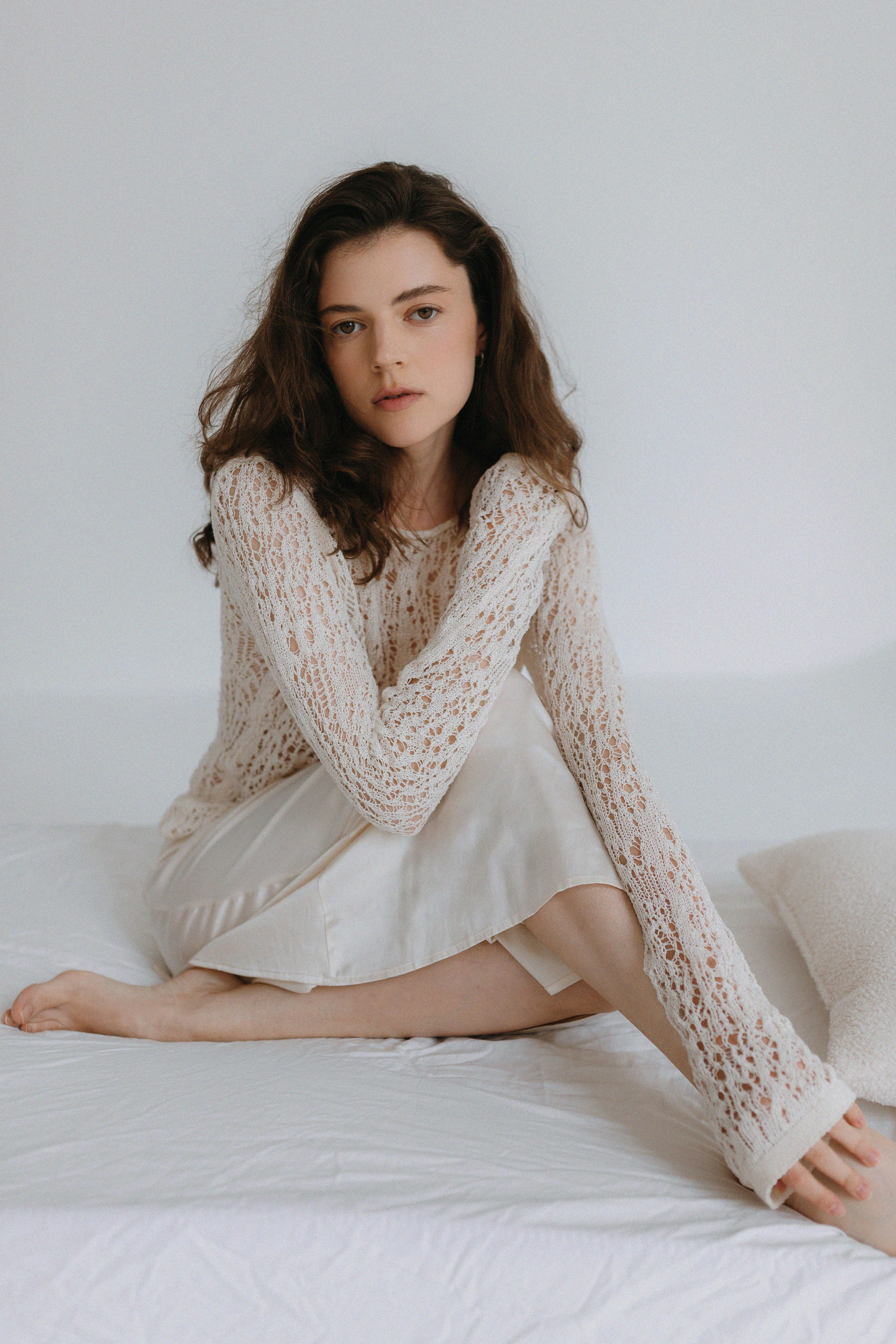Elegant Woman Sitting in Relaxed Pose on White Bed · Free Stock Photo