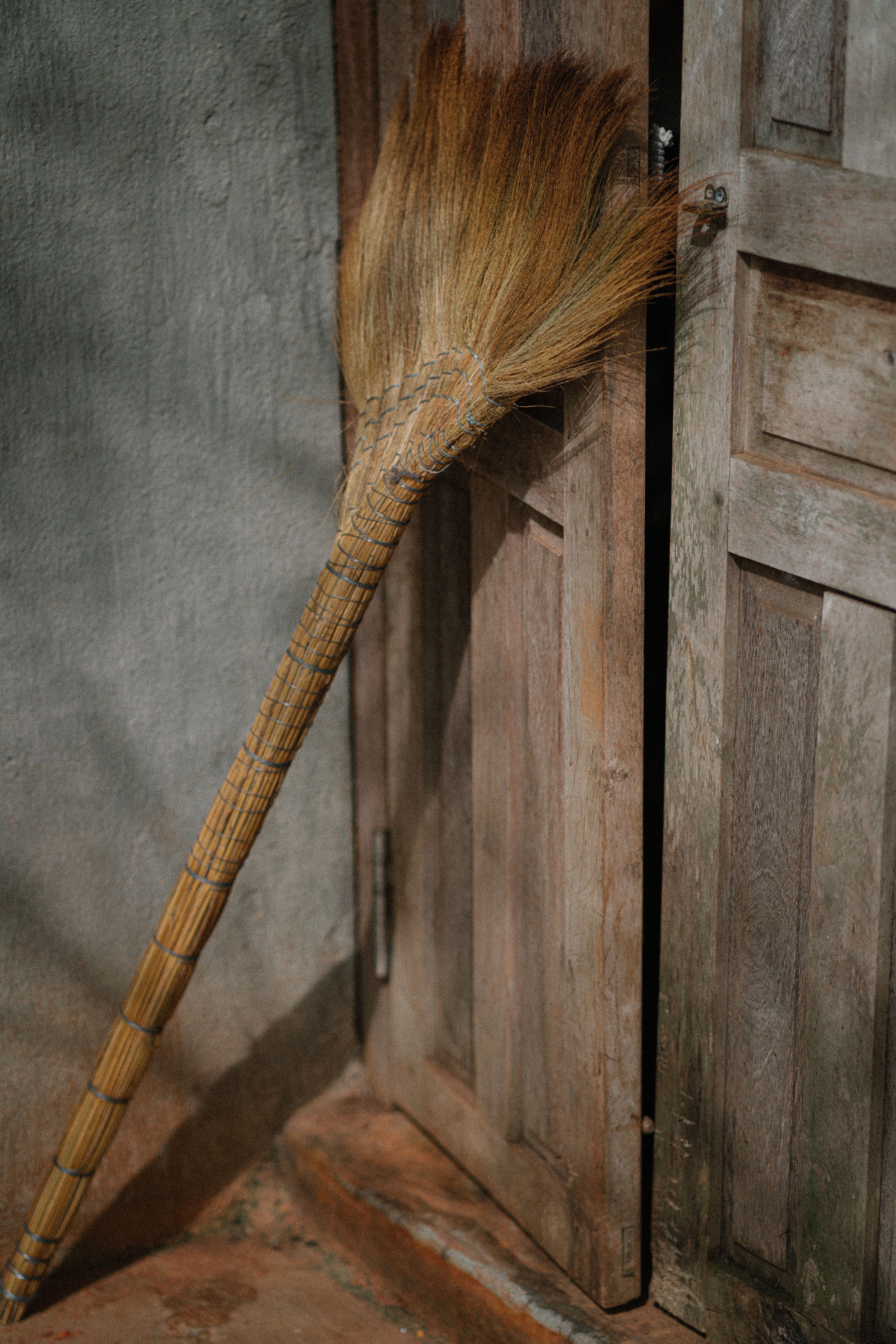 Rustic Straw Broom by Weathered Wooden Door · Free Stock Photo