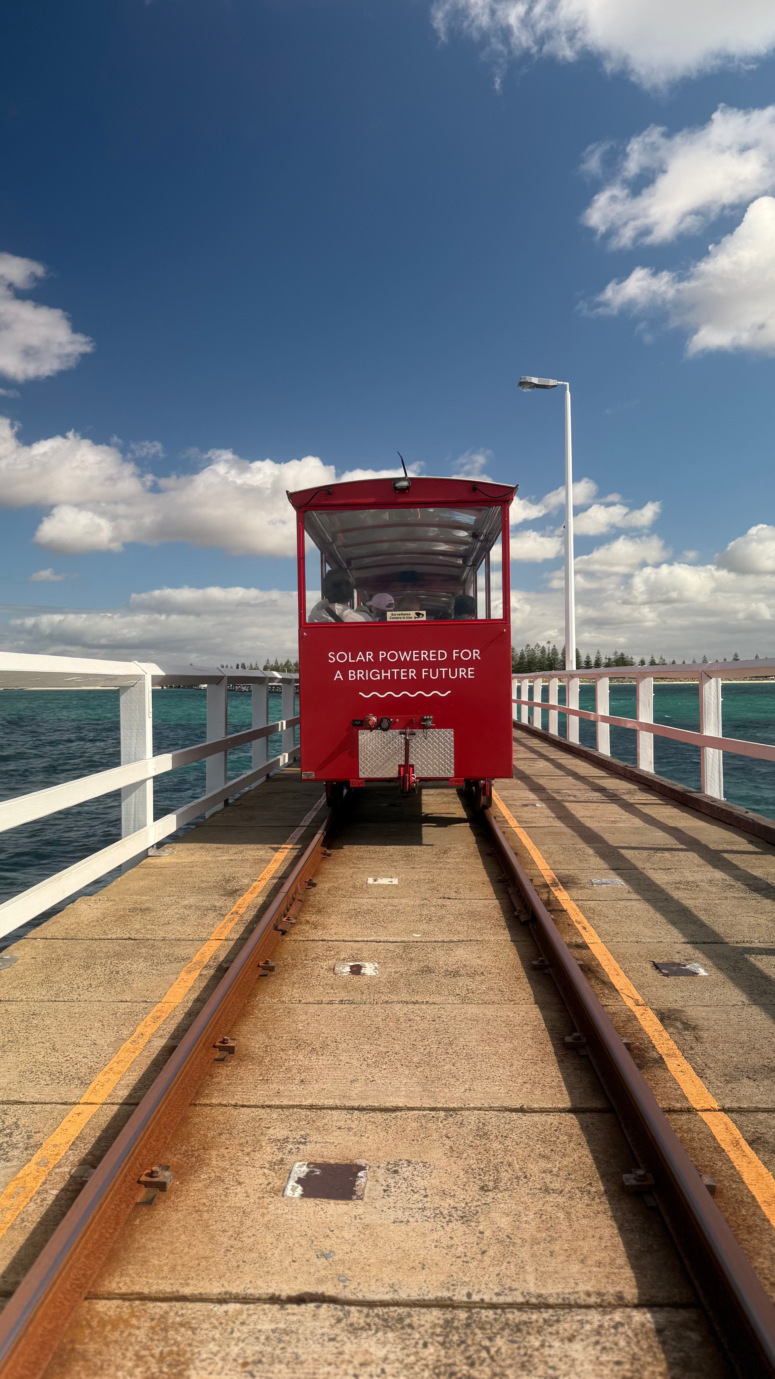 Red Solar-Powered Tram on Pier with Ocean View · Free Stock Photo