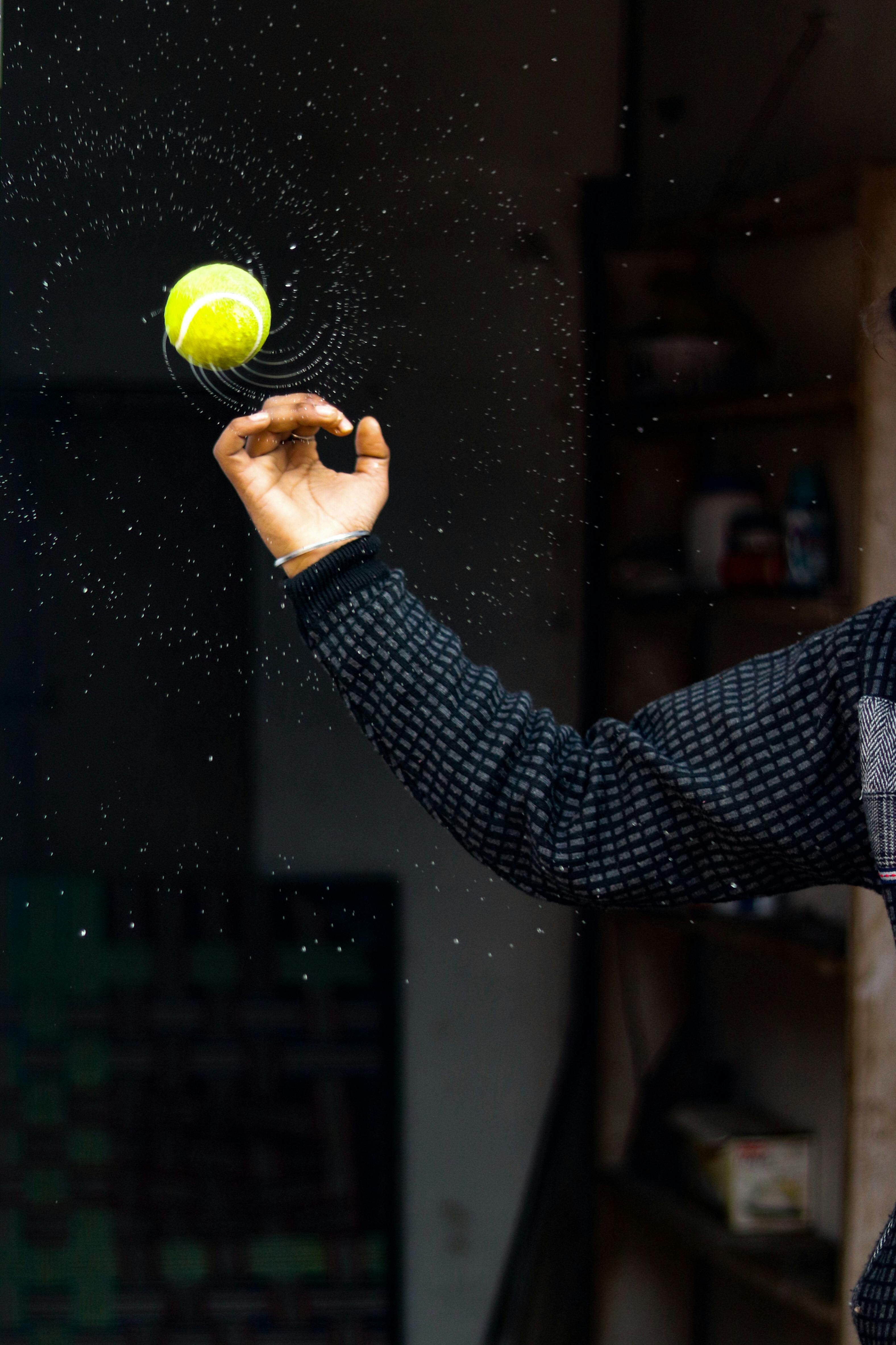 Crop athlete throwing tennis ball in water drops · Free Stock Photo