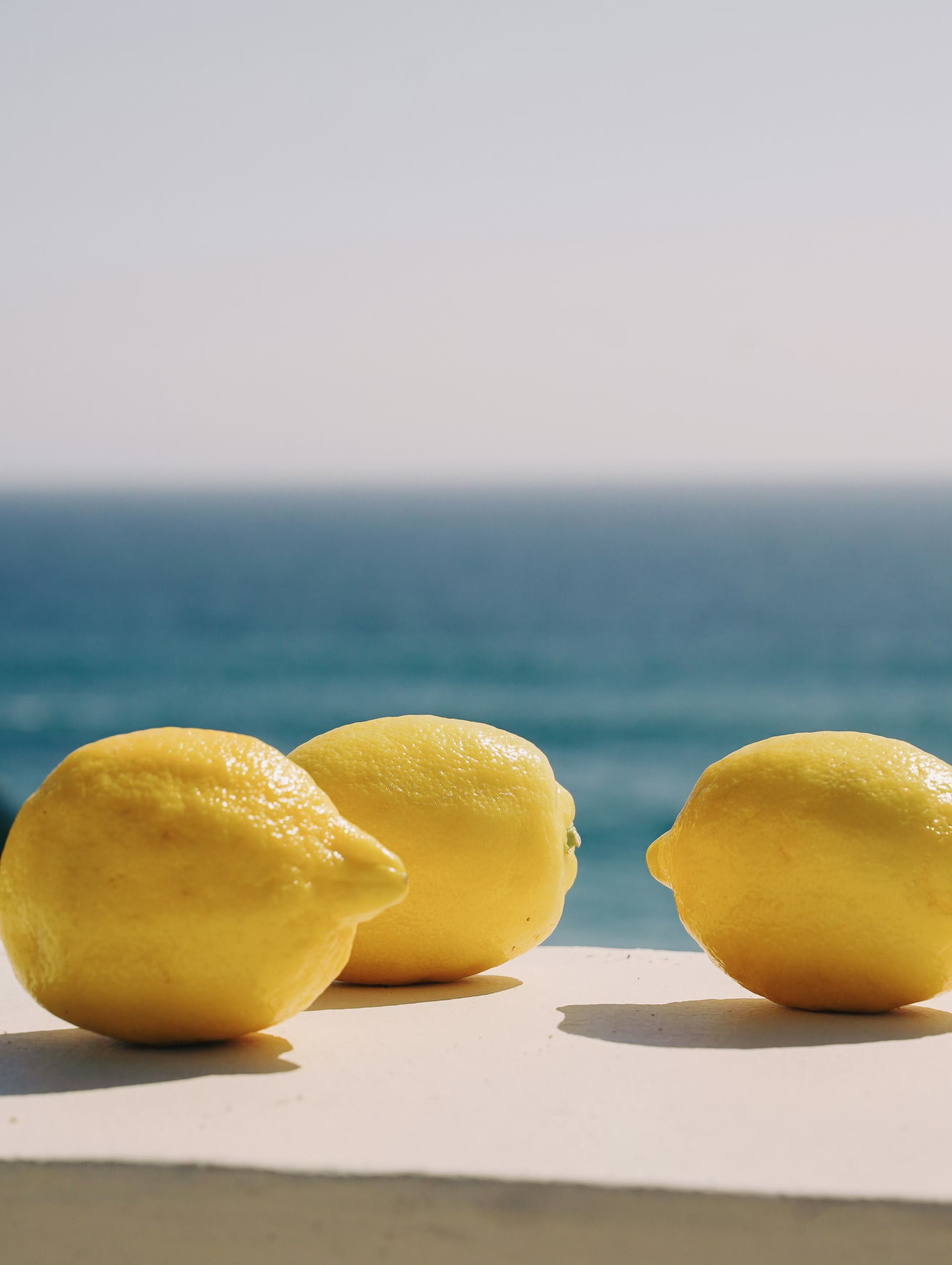 Bright Yellow Lemons by the Serene Ocean · Free Stock Photo