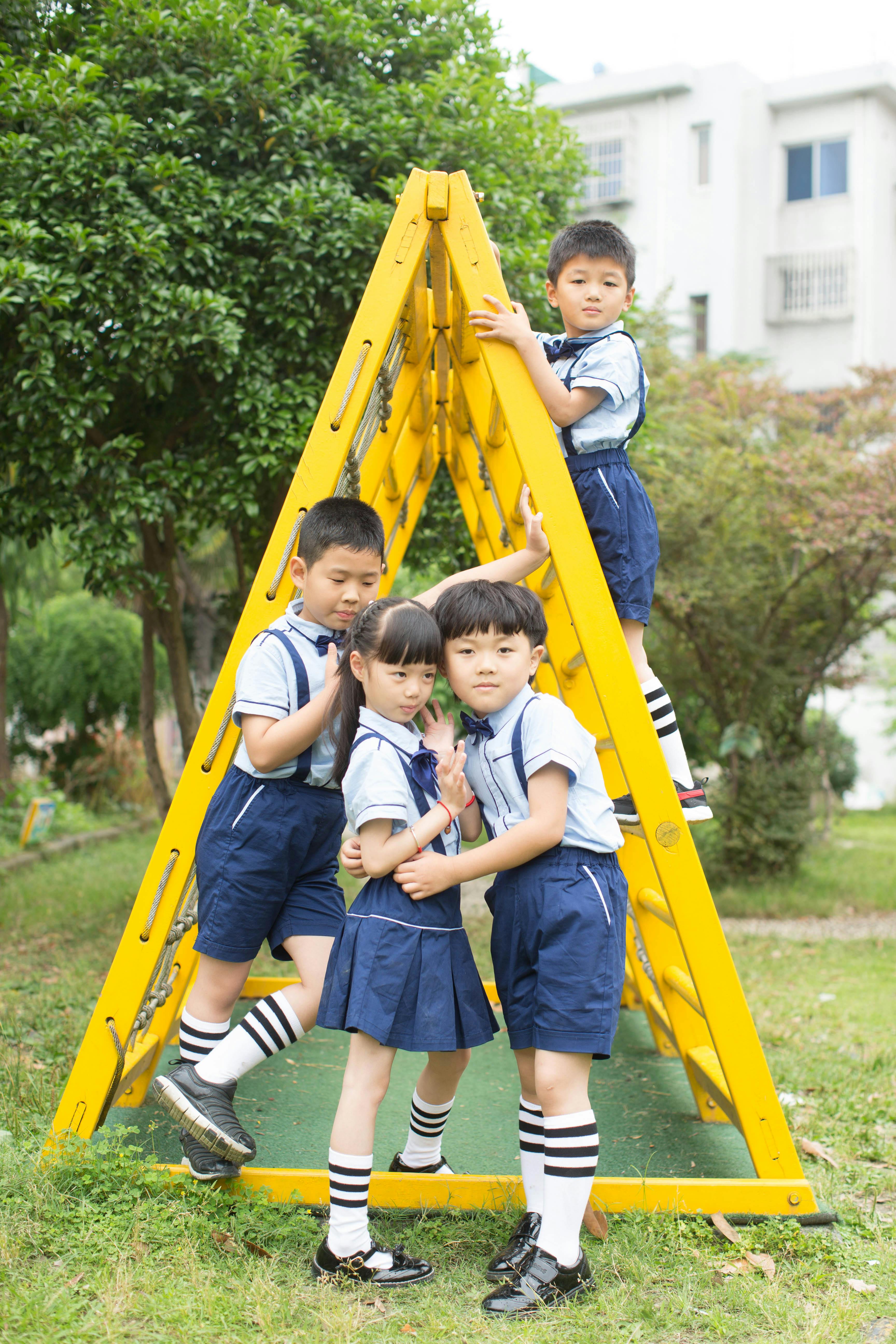 Children in Uniforms Playing on Triangle Frame · Free Stock Photo