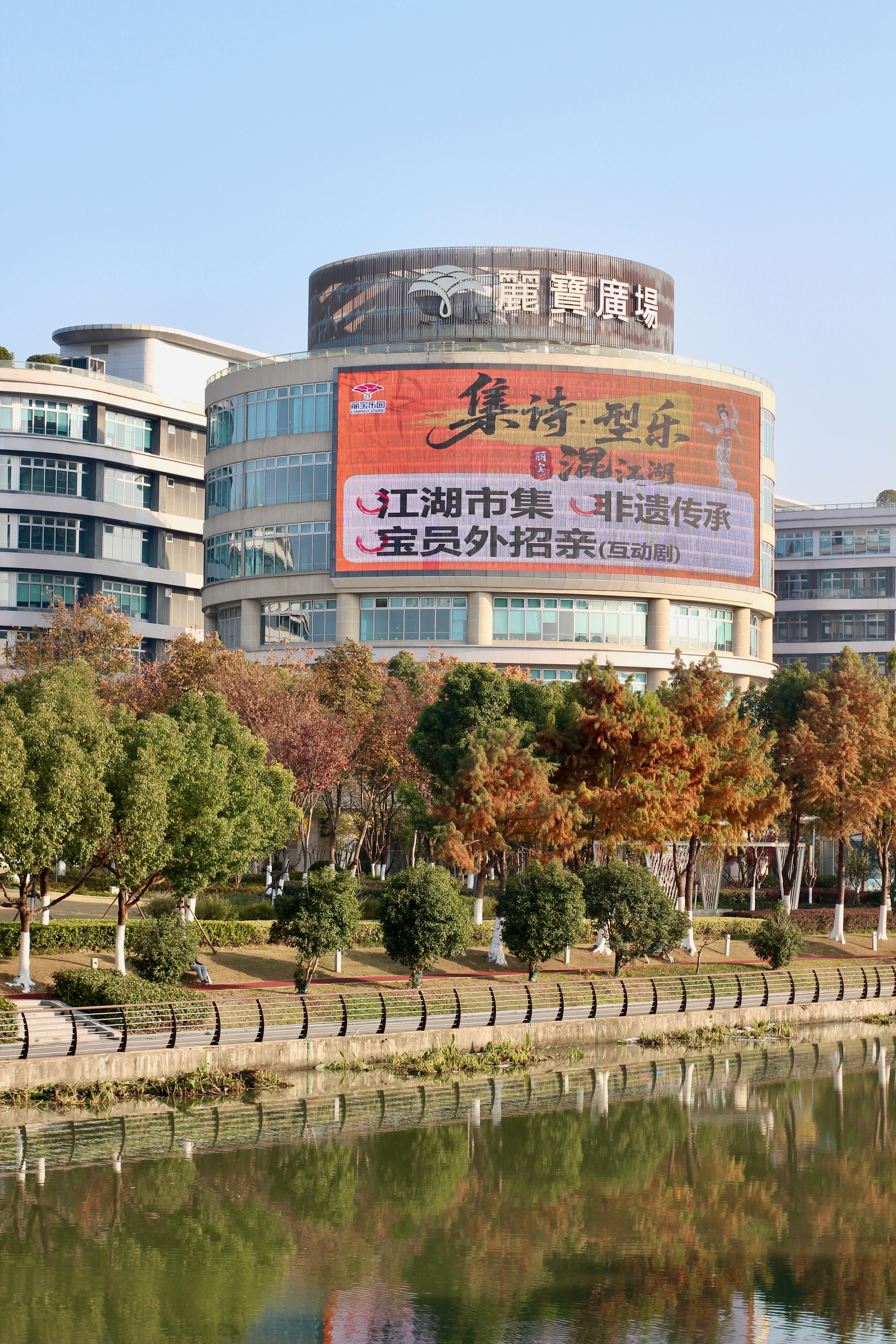 Large Building with Advertising Banner and Trees · Free Stock Photo