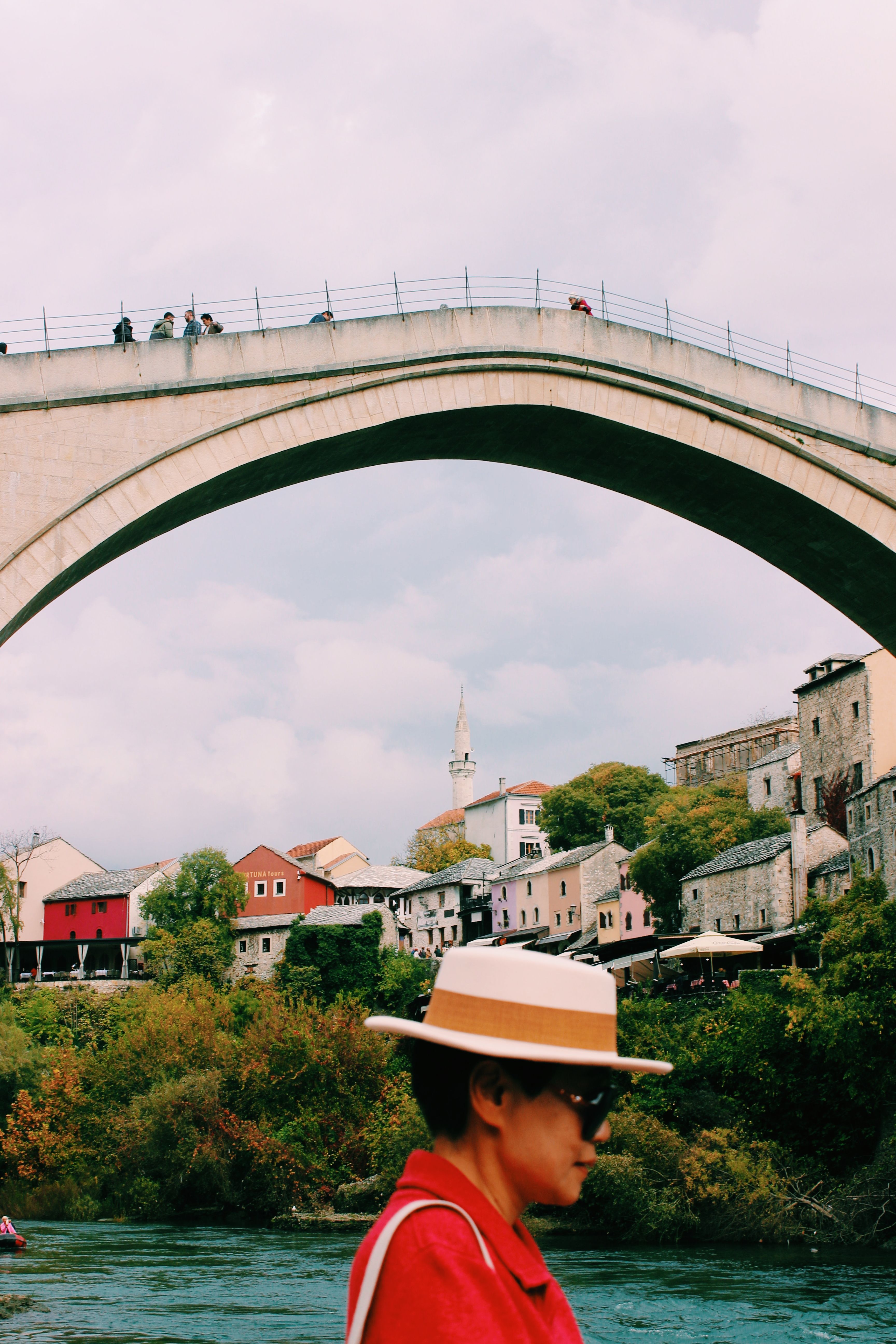 Woman in hat passing beneath historic bridge · Free Stock Photo