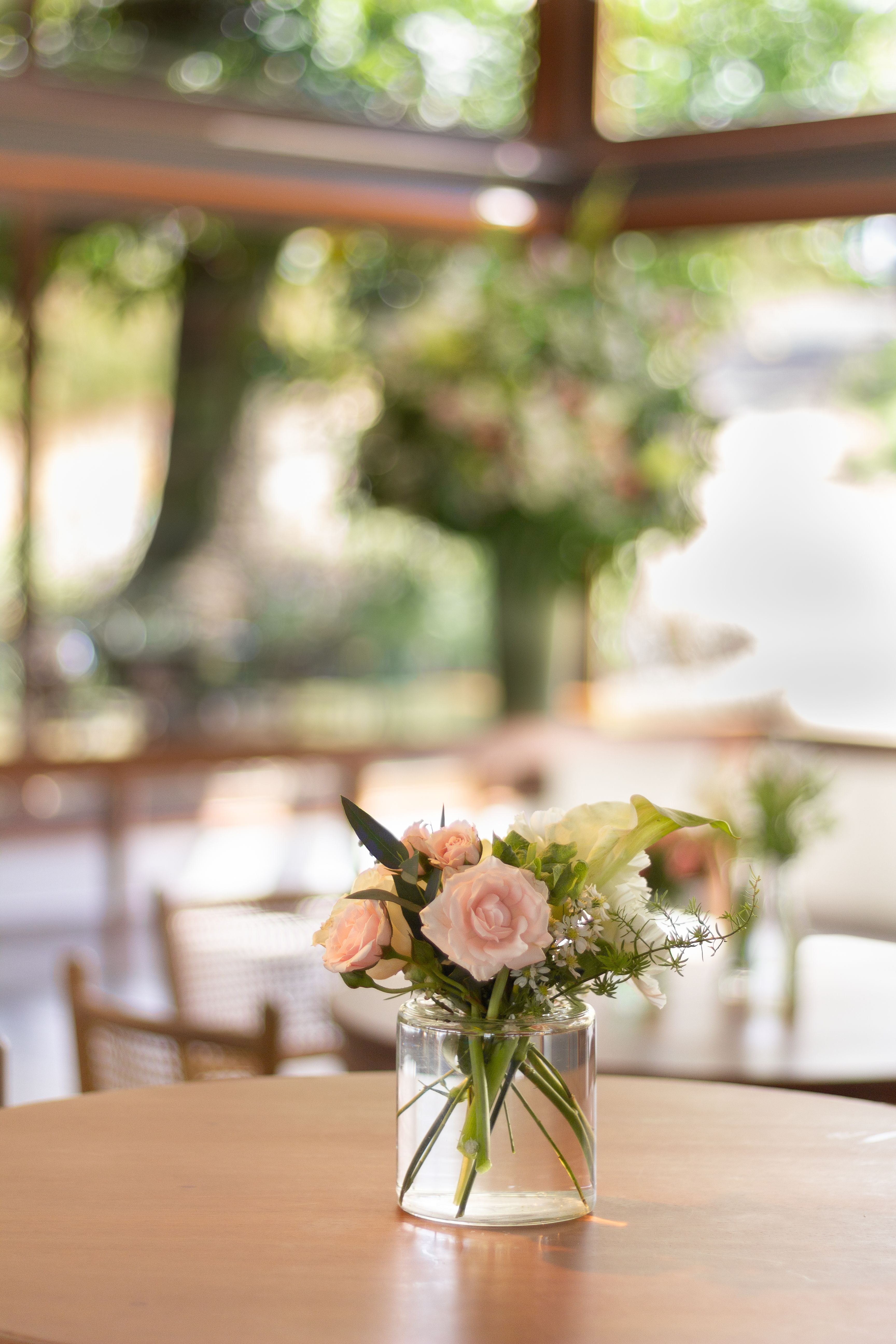 Elegant Floral Arrangement in Sunny Café Setting · Free Stock Photo