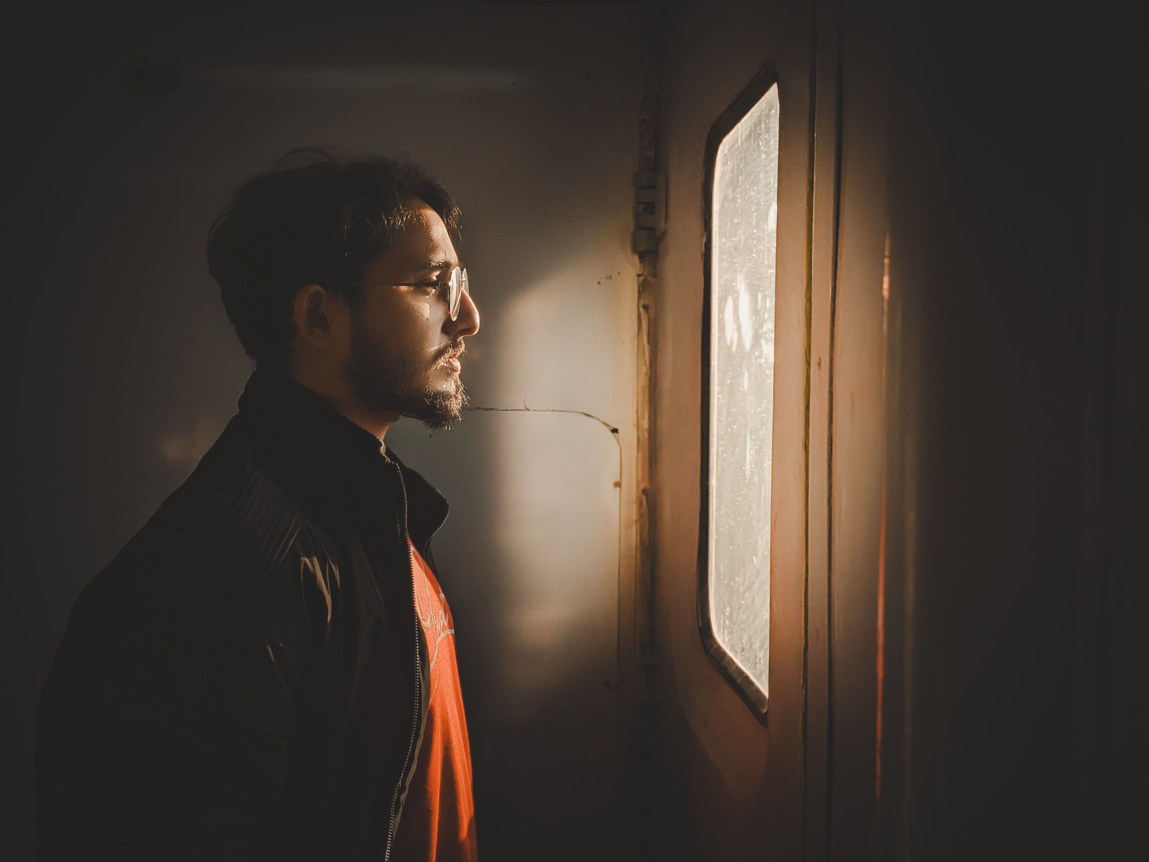 Pensive Man Gazing Out Window in Warm Light · Free Stock Photo