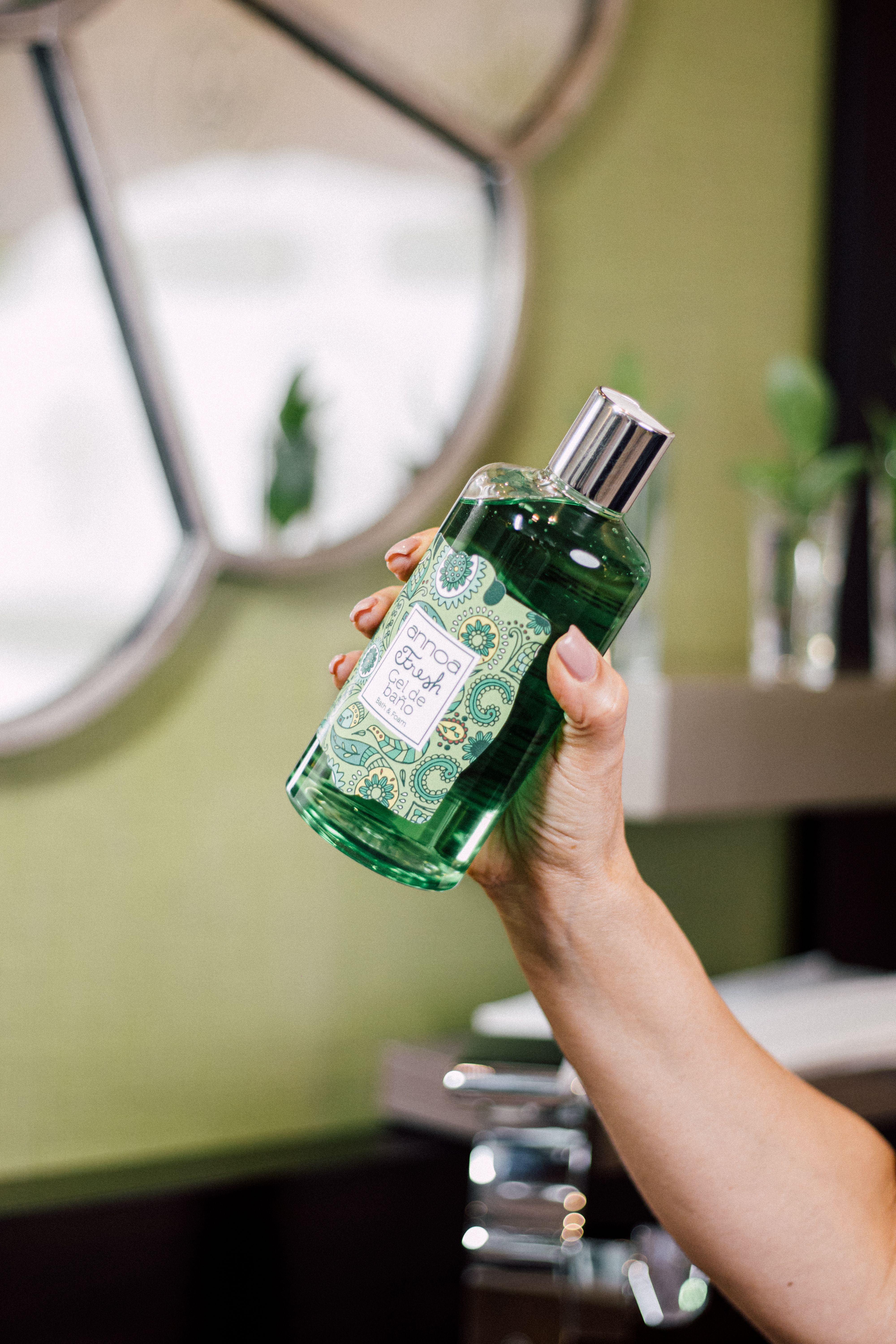 Hand holding a bottle of green body lotion · Free Stock Photo