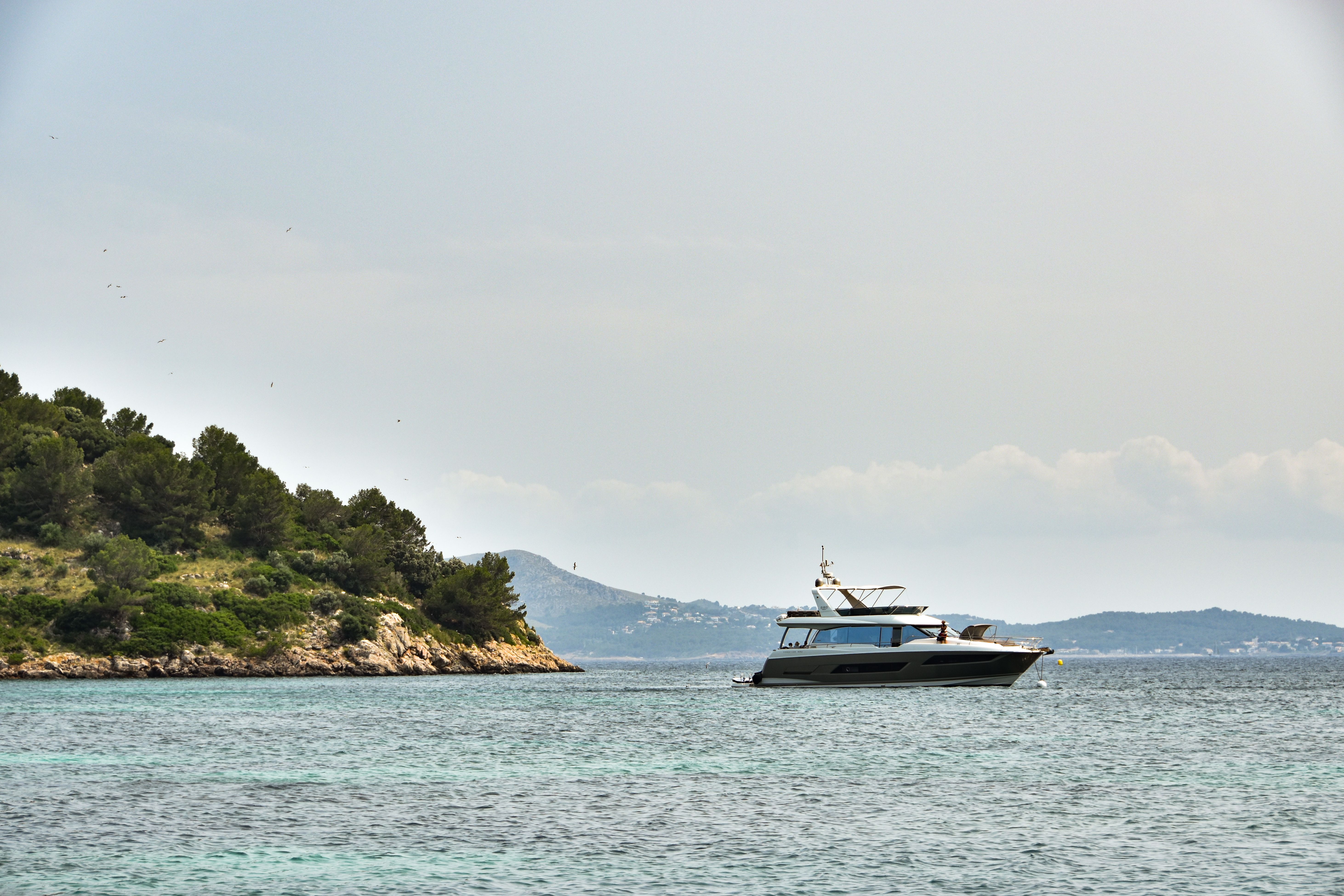 Luxury Yacht Sailing Near a Scenic Island Shore · Free Stock Photo
