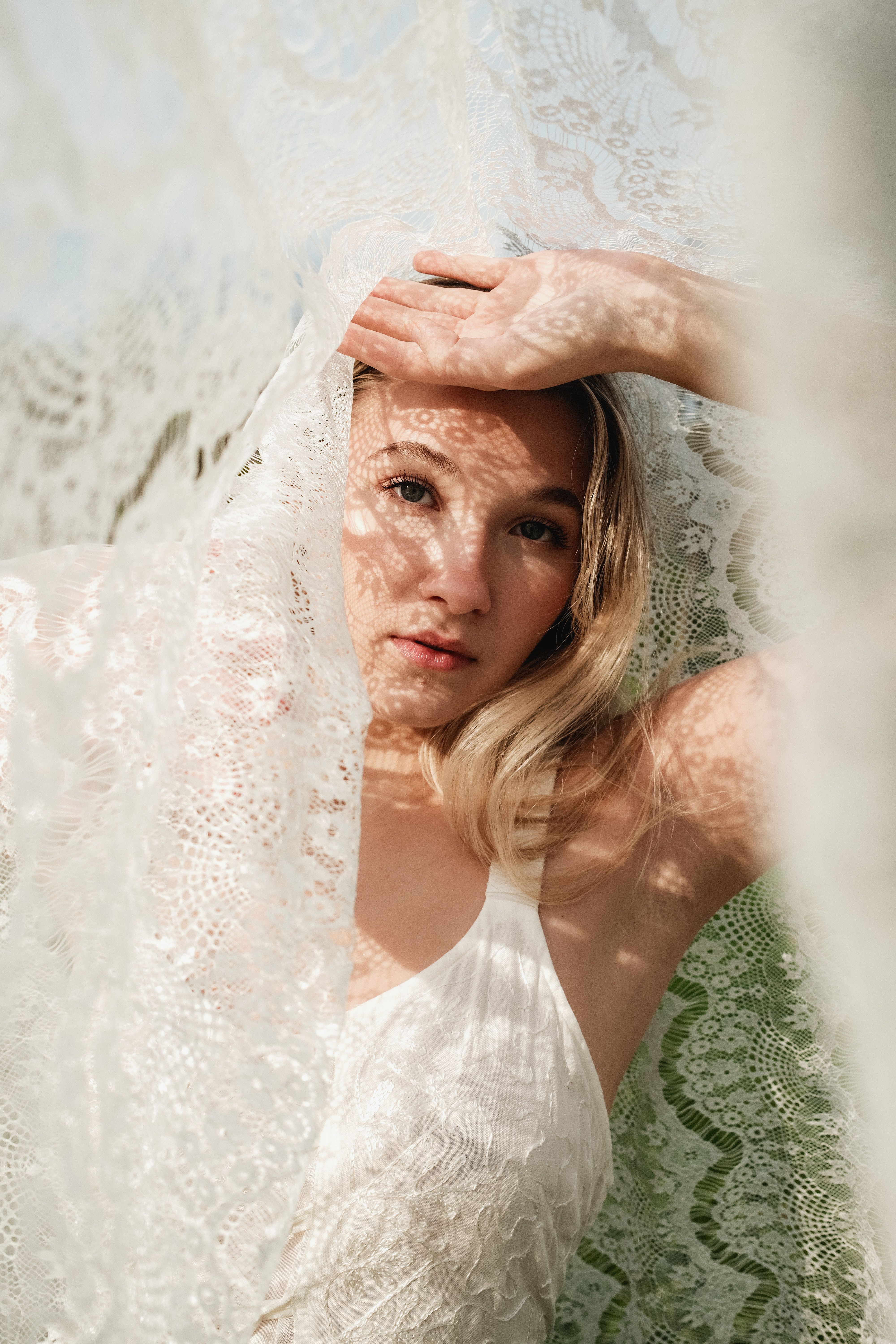 Smiling Woman Posing with Lace Shadows Outdoors · Free Stock Photo