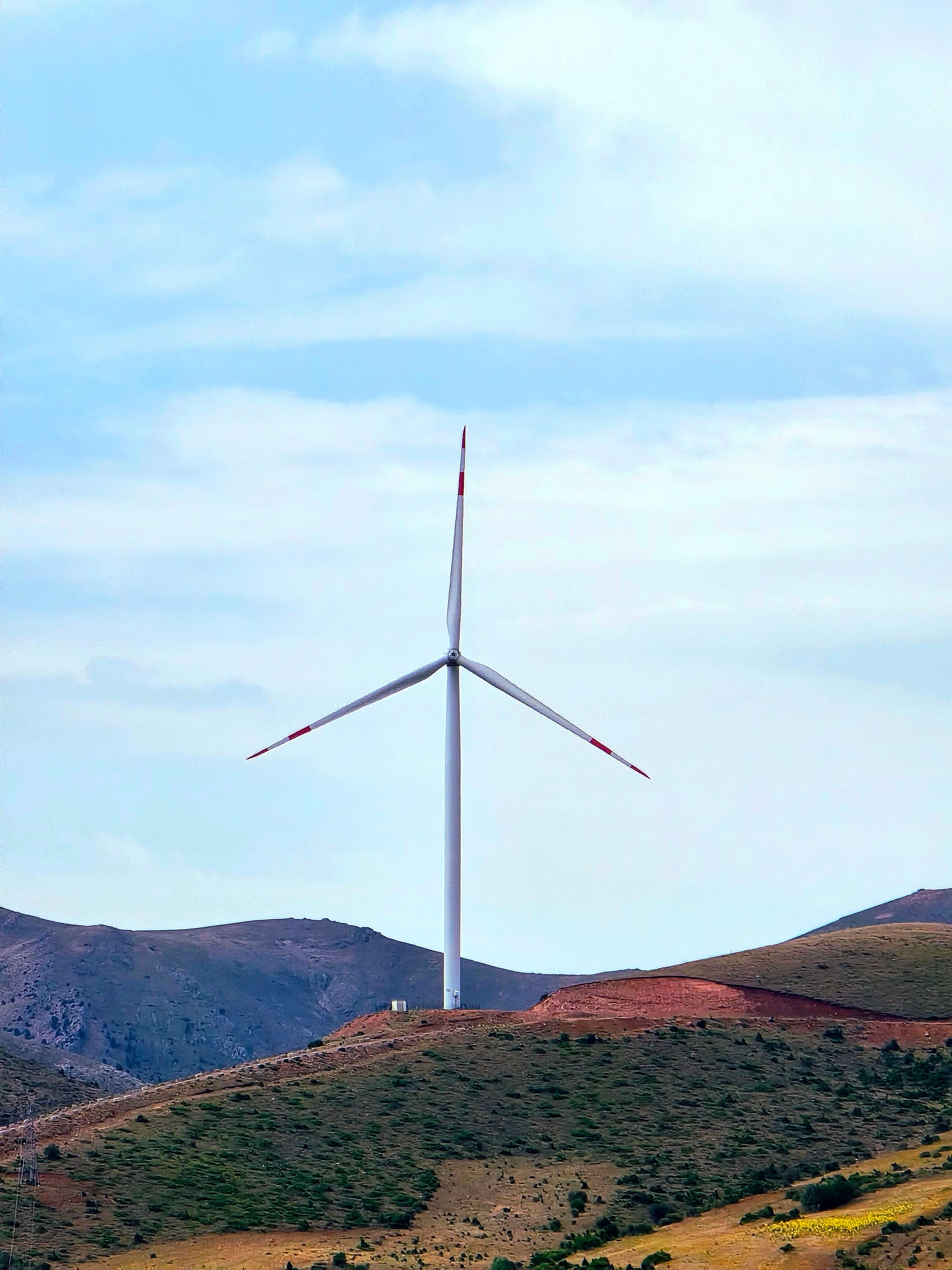 Wind Turbine on Rolling Hills Under Blue Sky · Free Stock Photo