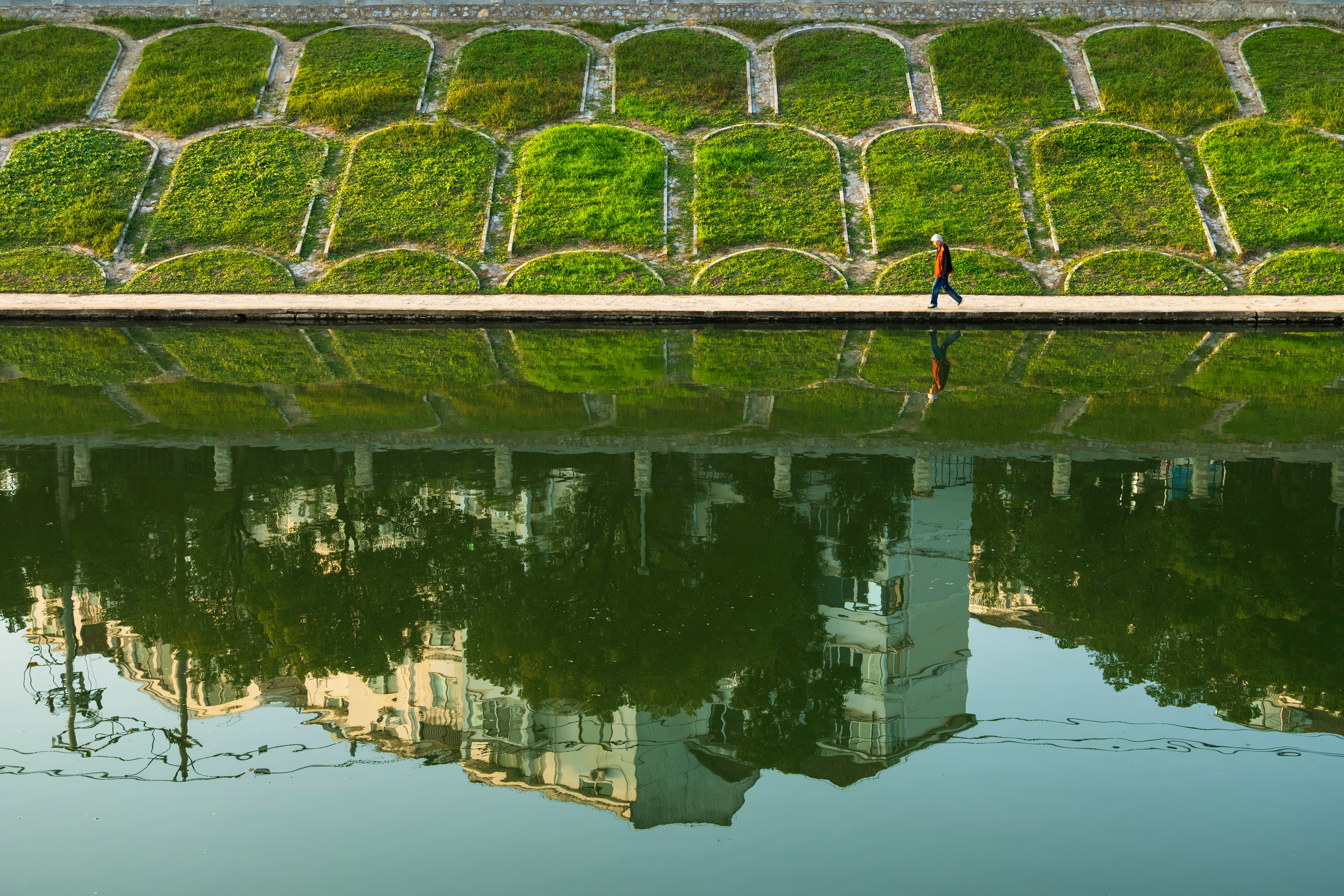 Man Walking by Riverside with City Reflection · Free Stock Photo