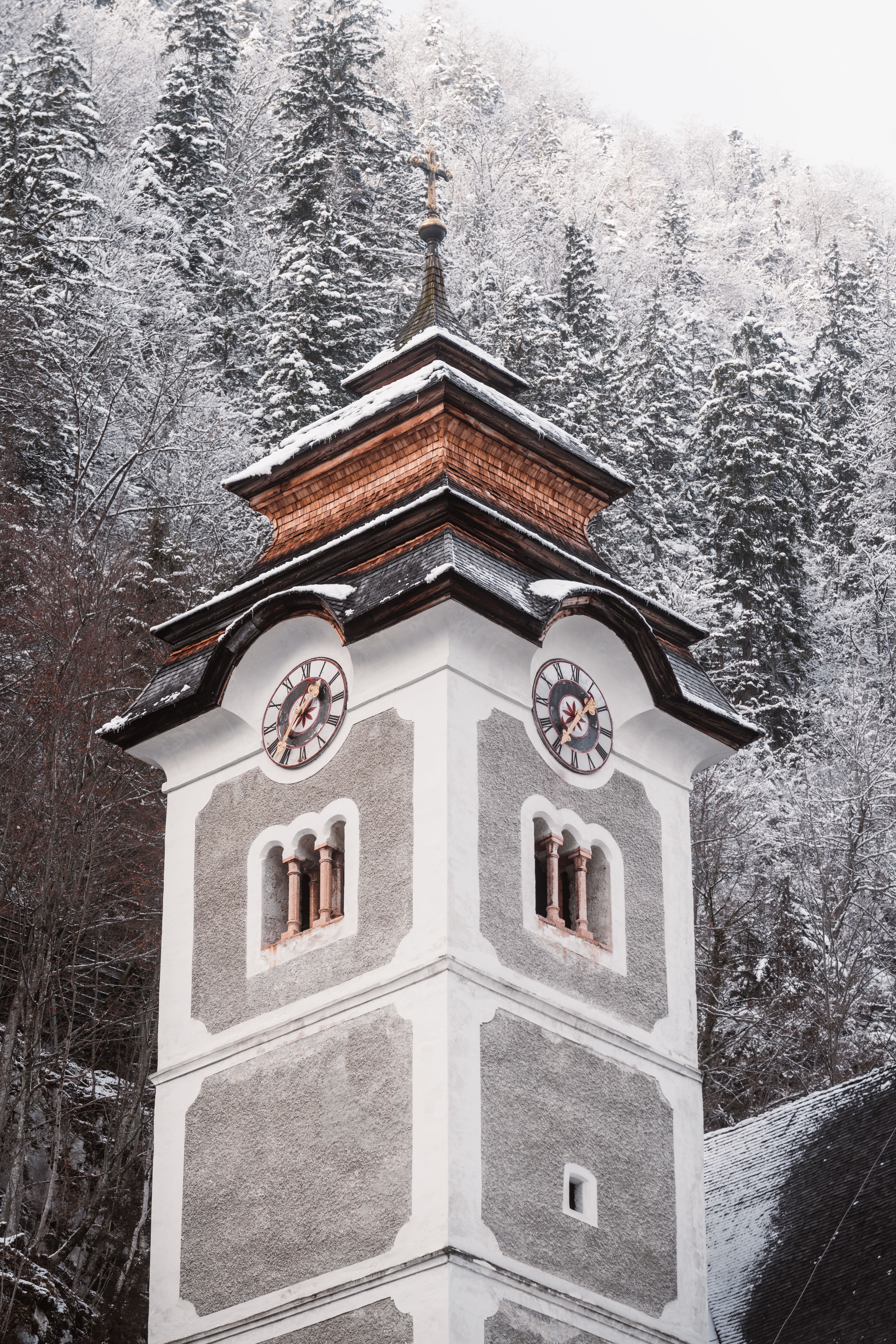 Snow-Covered Alpine Church Tower with Forest · Free Stock Photo