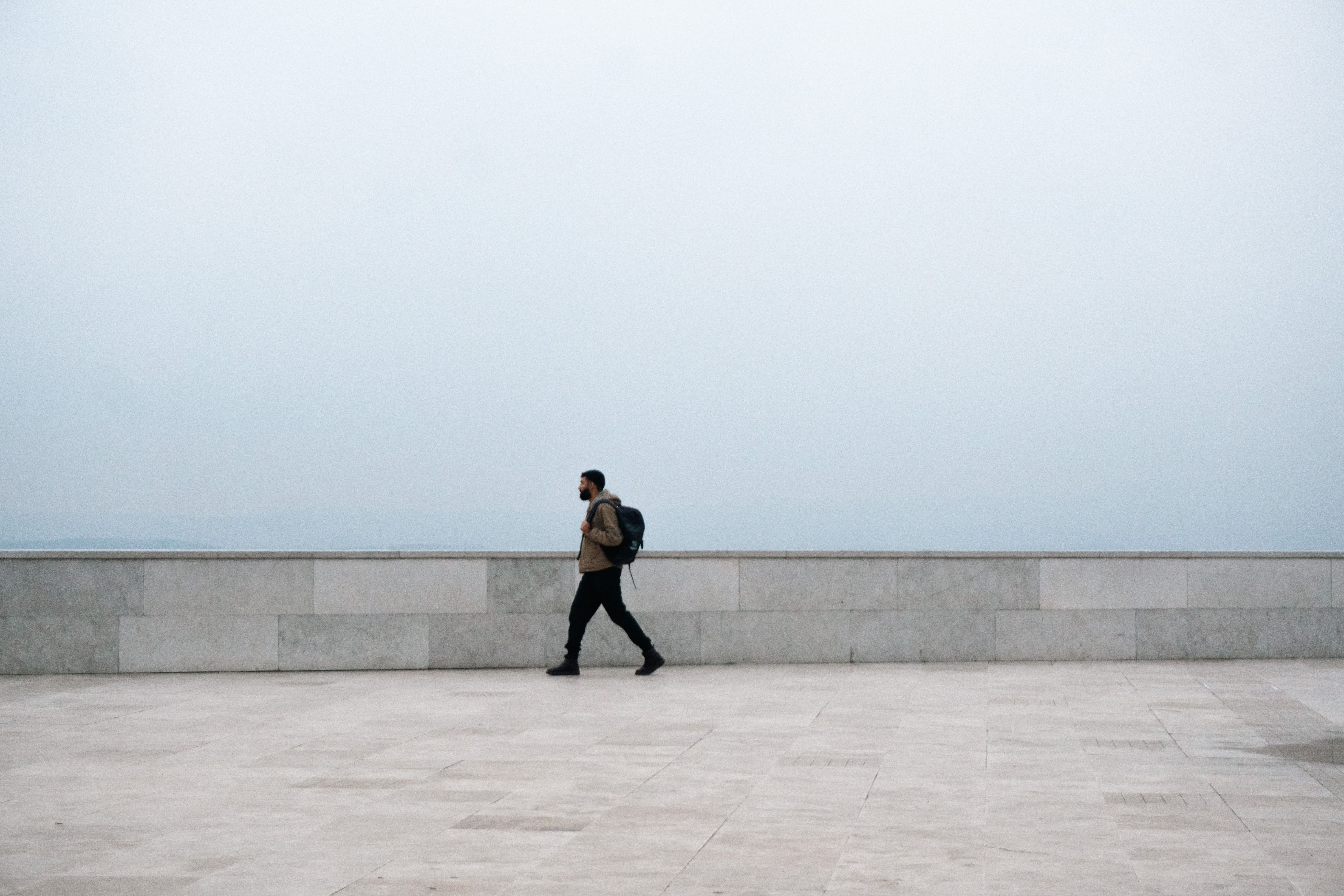 Man Walking on Minimalist Outdoor Walkway · Free Stock Photo