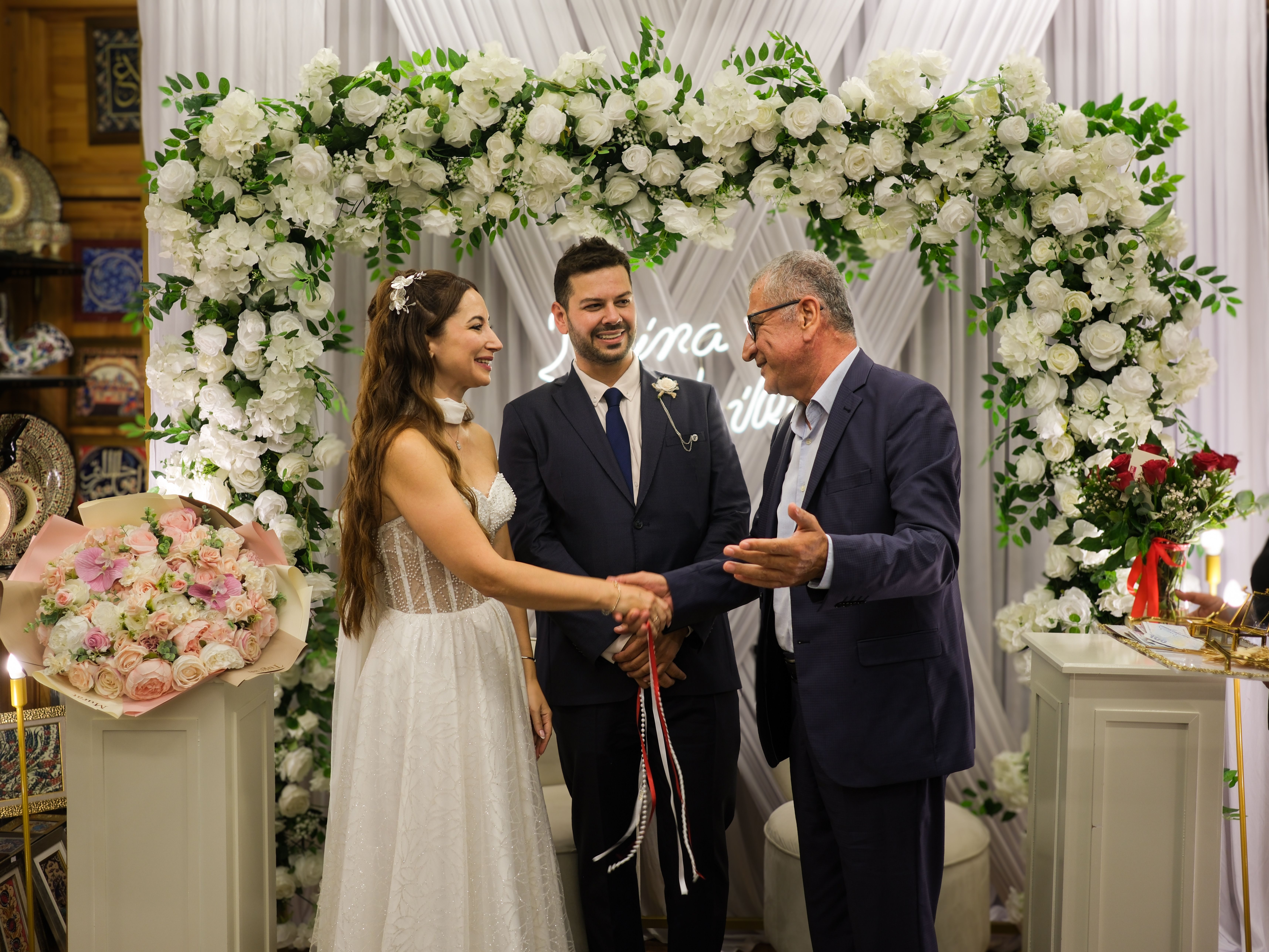 Celebratory Wedding Handshake Under Floral Arch · Free Stock Photo
