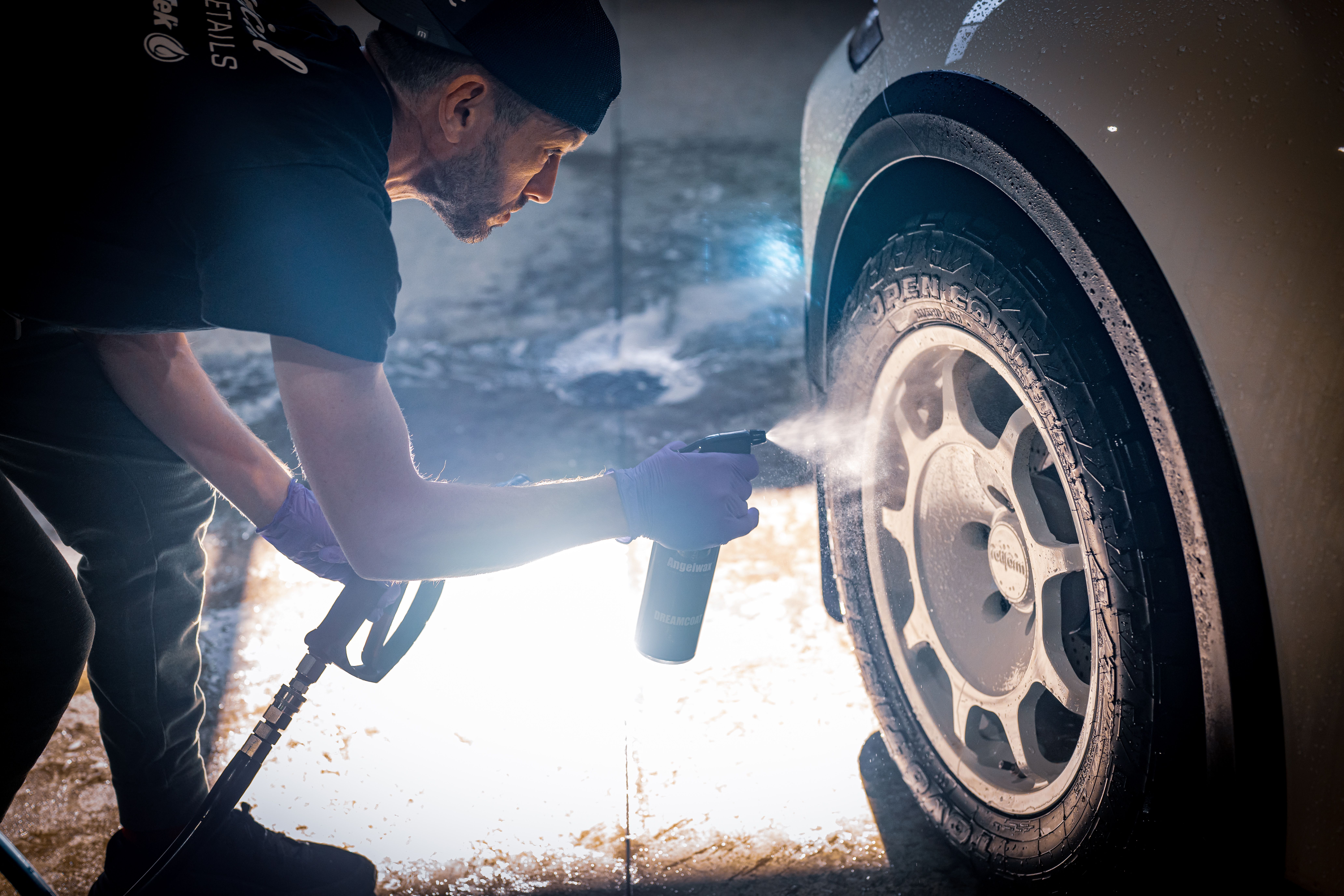Man Cleaning Car Tire with Spray Bottle at Detail Shop · Free Stock Photo