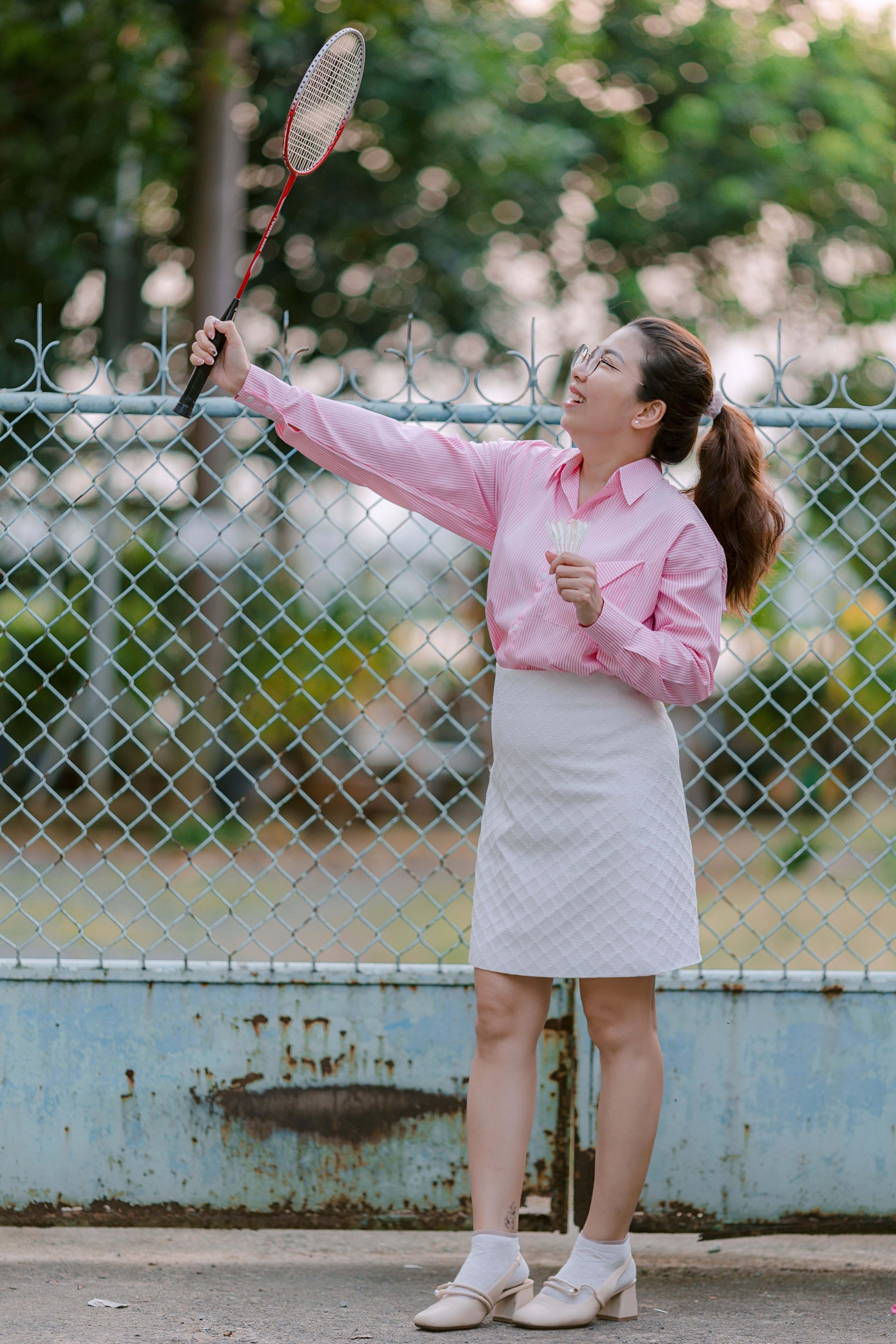 Woman playing badminton outdoors in pink shirt · Free Stock Photo