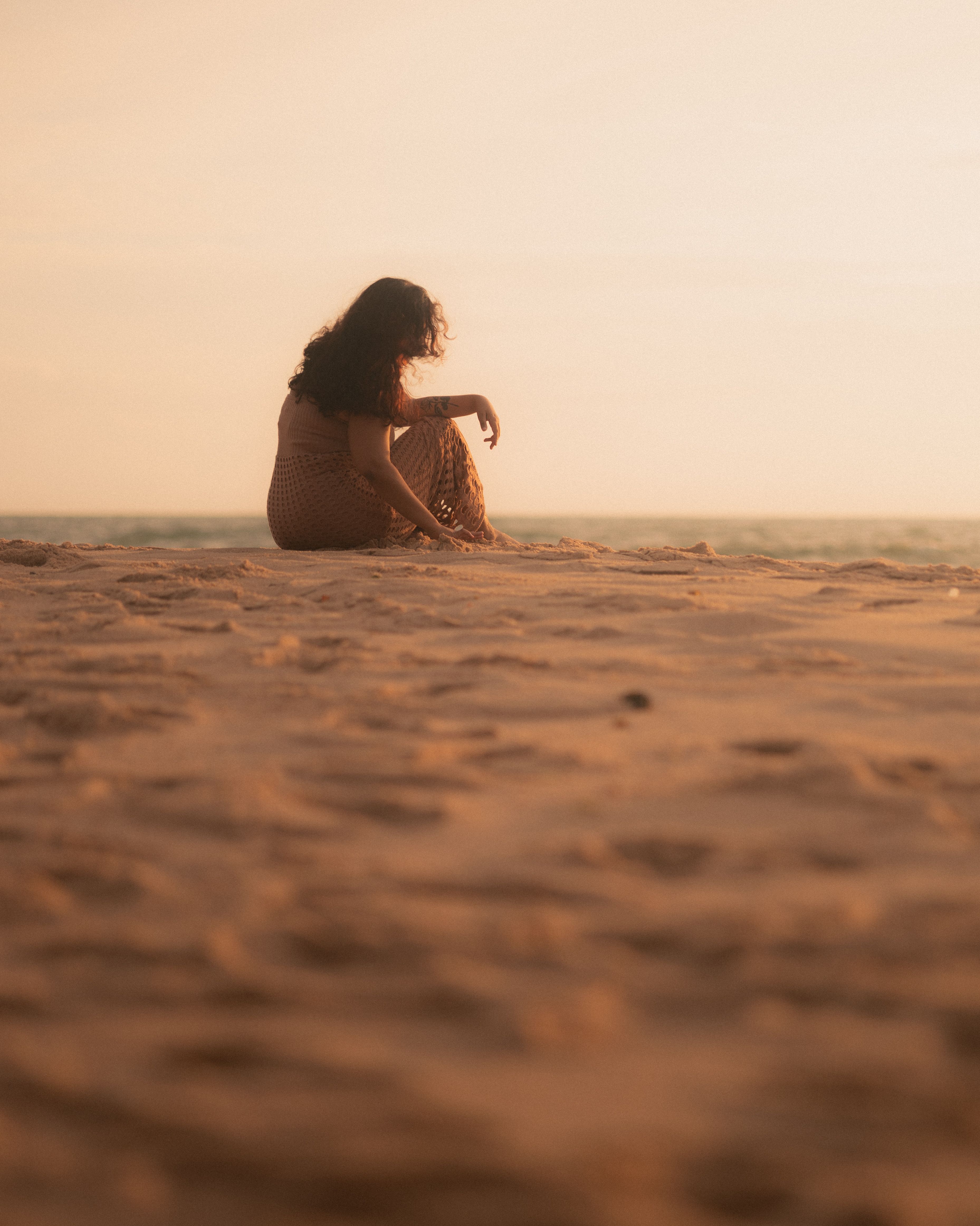 Silhouette of Woman Sitting on Beach at Sunset · Free Stock Photo